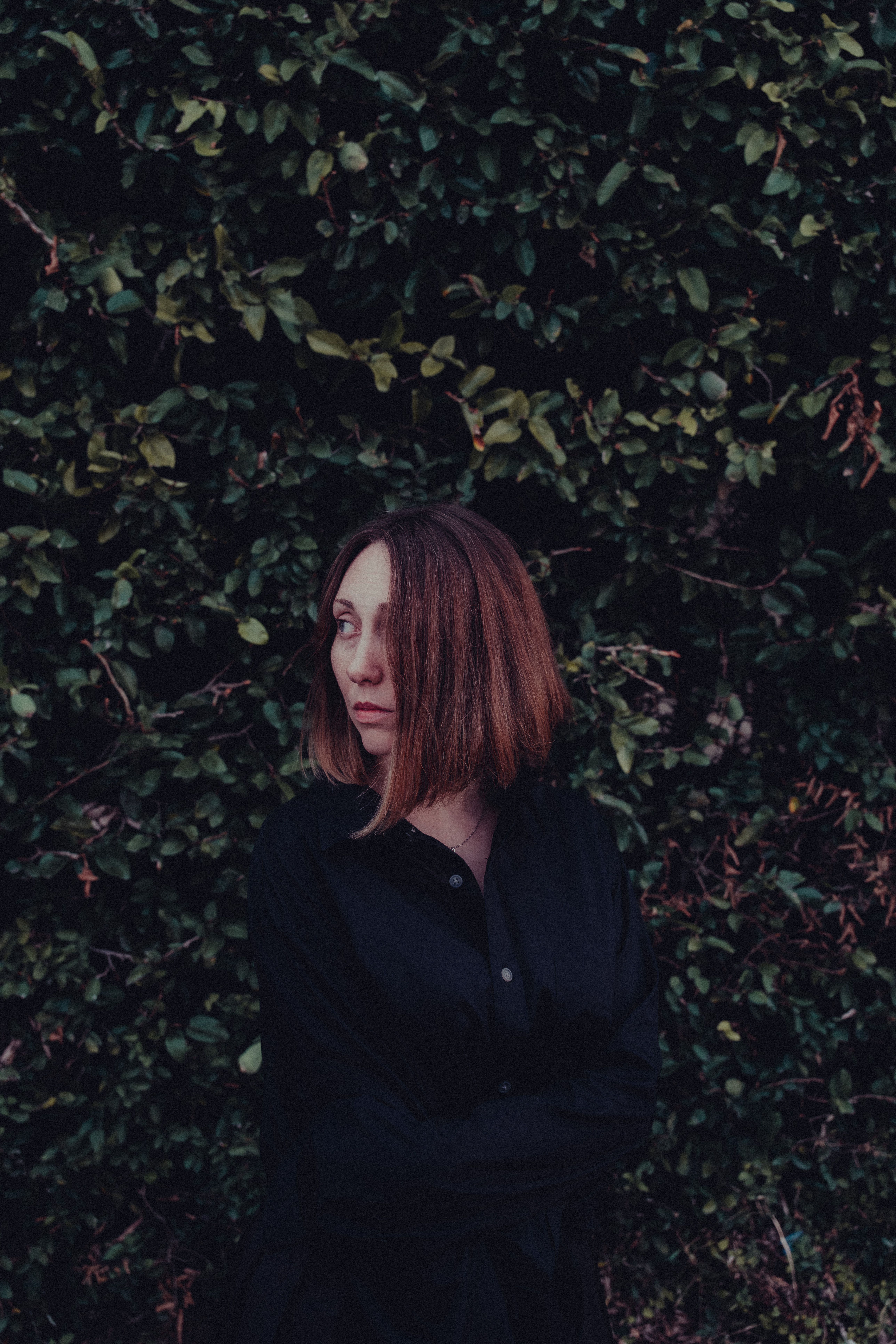 Portrait of Woman in Black Shirt Among Green Hedge · Free Stock Photo