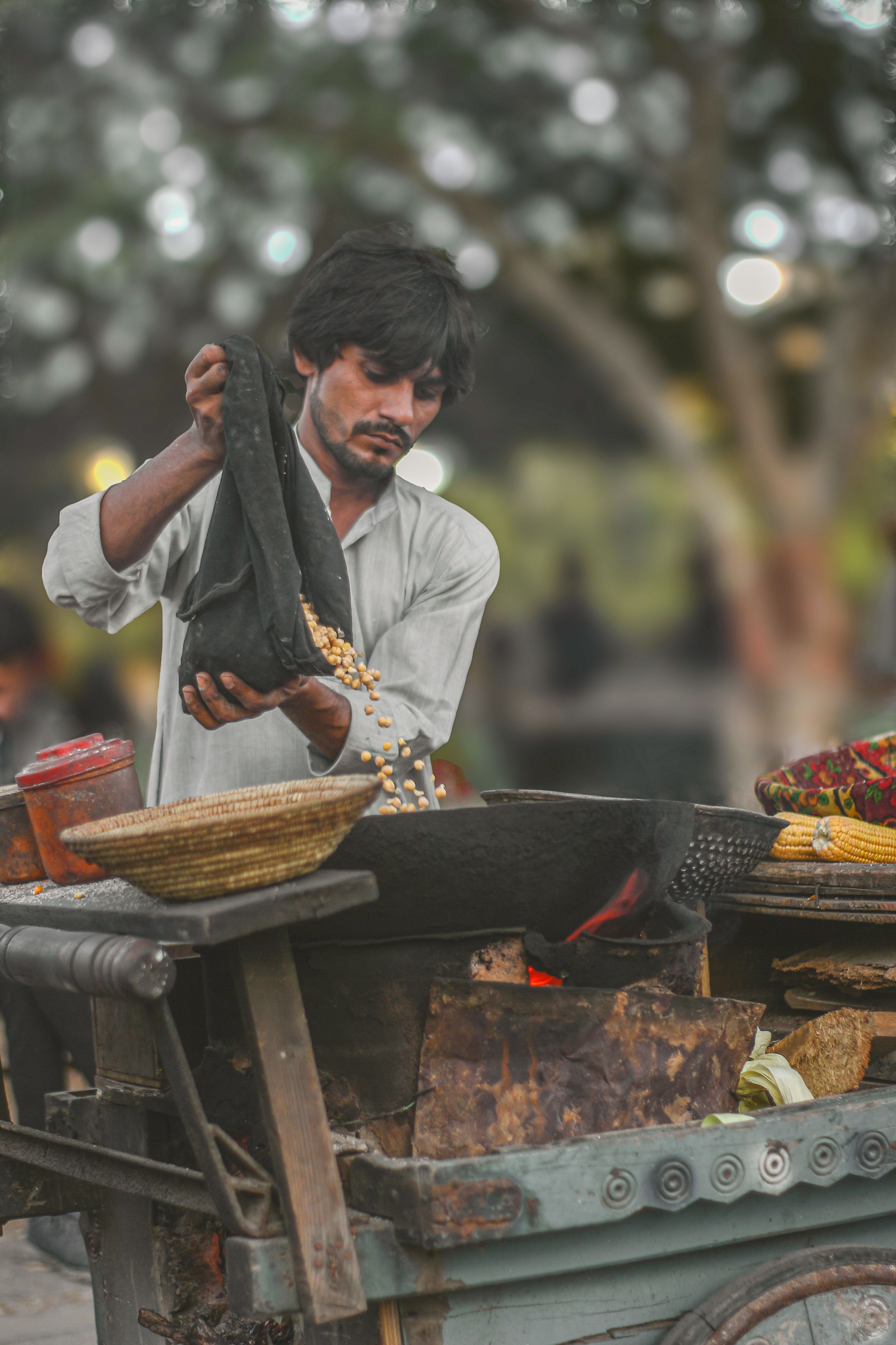 Man Baking Nuts in Pot on Fire · Free Stock Photo