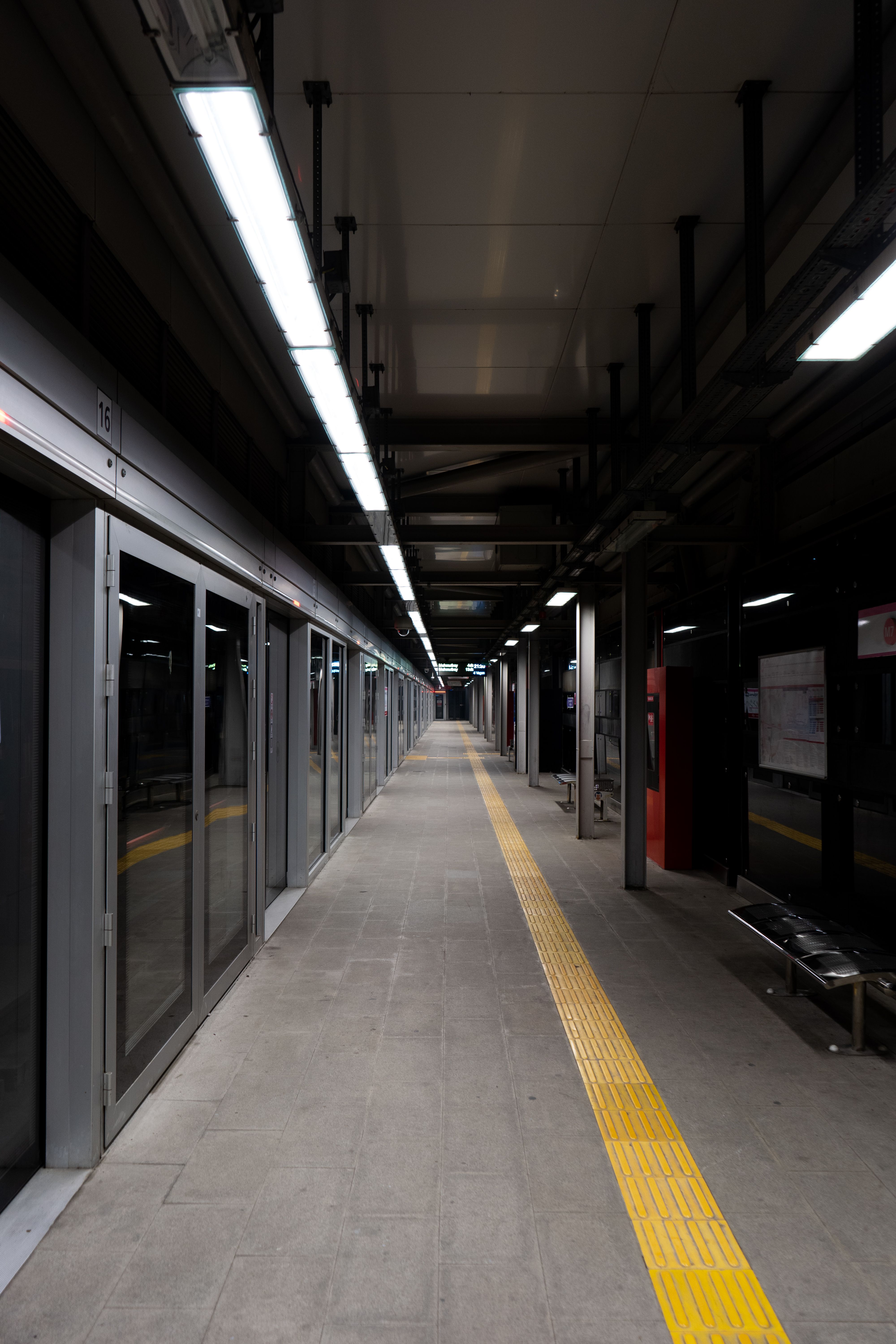 A subway station with a long walkway and a yellow line · Free Stock Photo