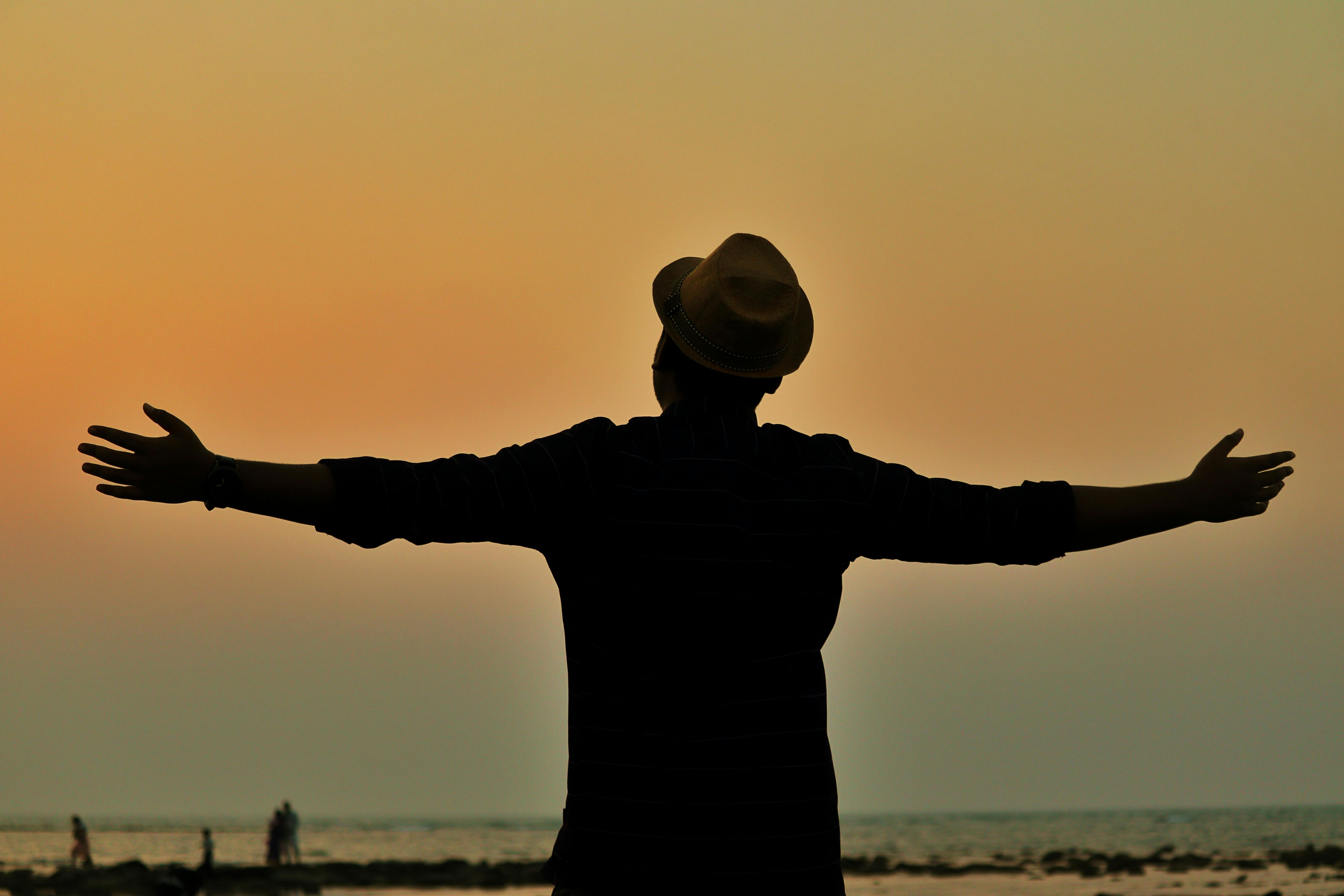 Silhouette of a Person Standing with Arms Outstretched · Free Stock Photo