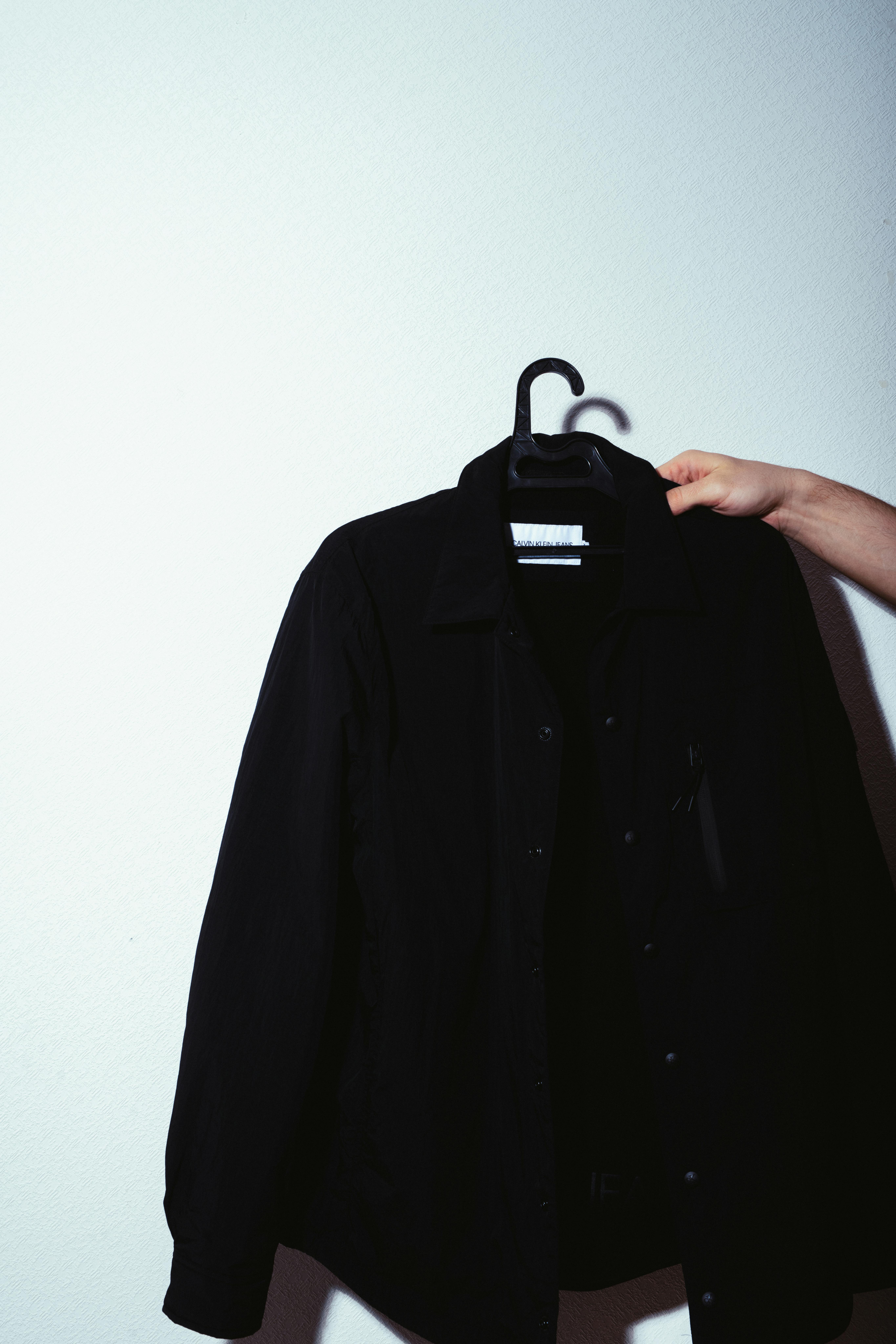 Person Holding Black Jacket With Hanger · Free Stock Photo