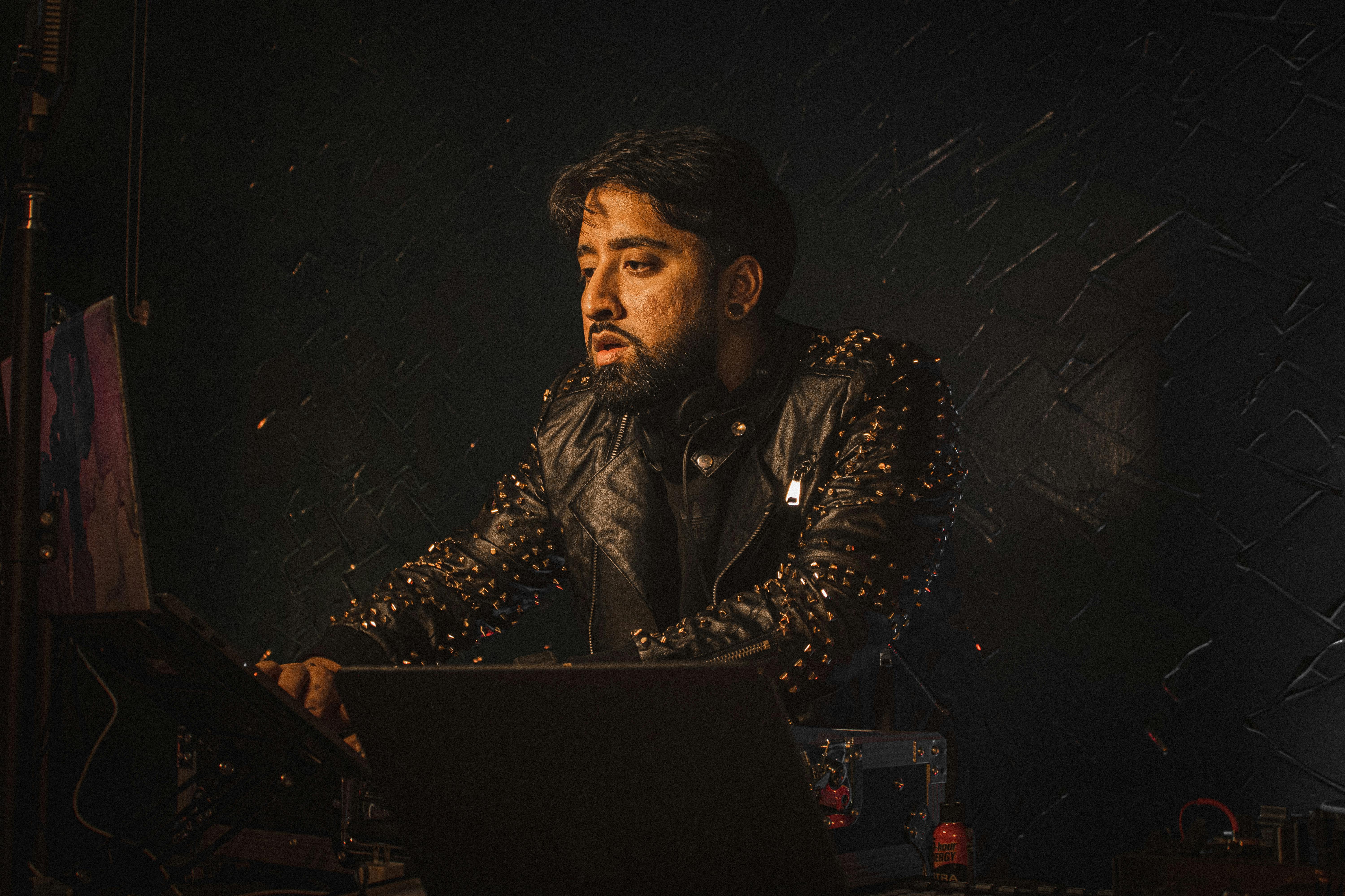 Man in a Leather Jacket Mixing Music on a Console · Free Stock Photo