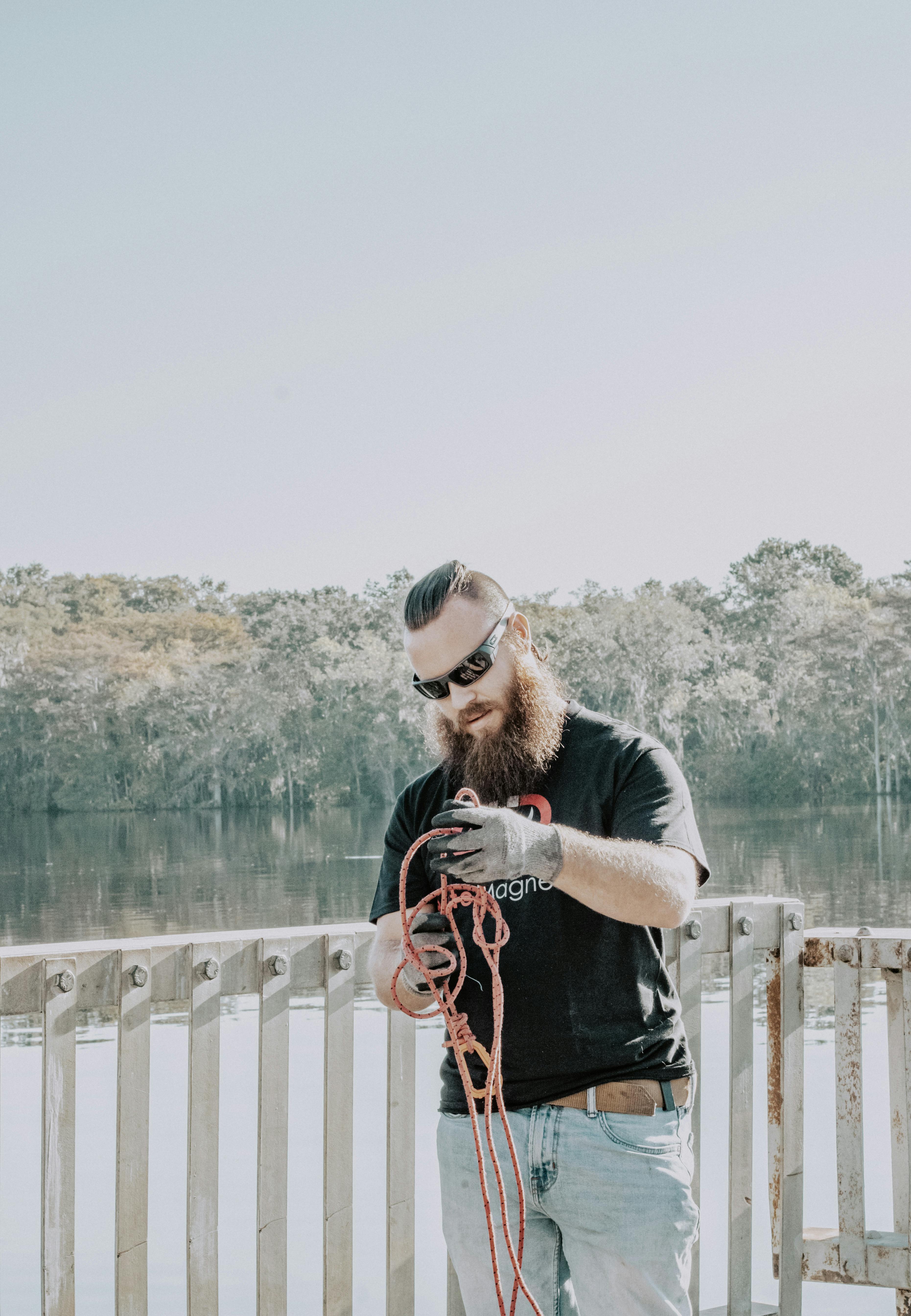 Man Untangling Rope on a Bridge · Free Stock Photo