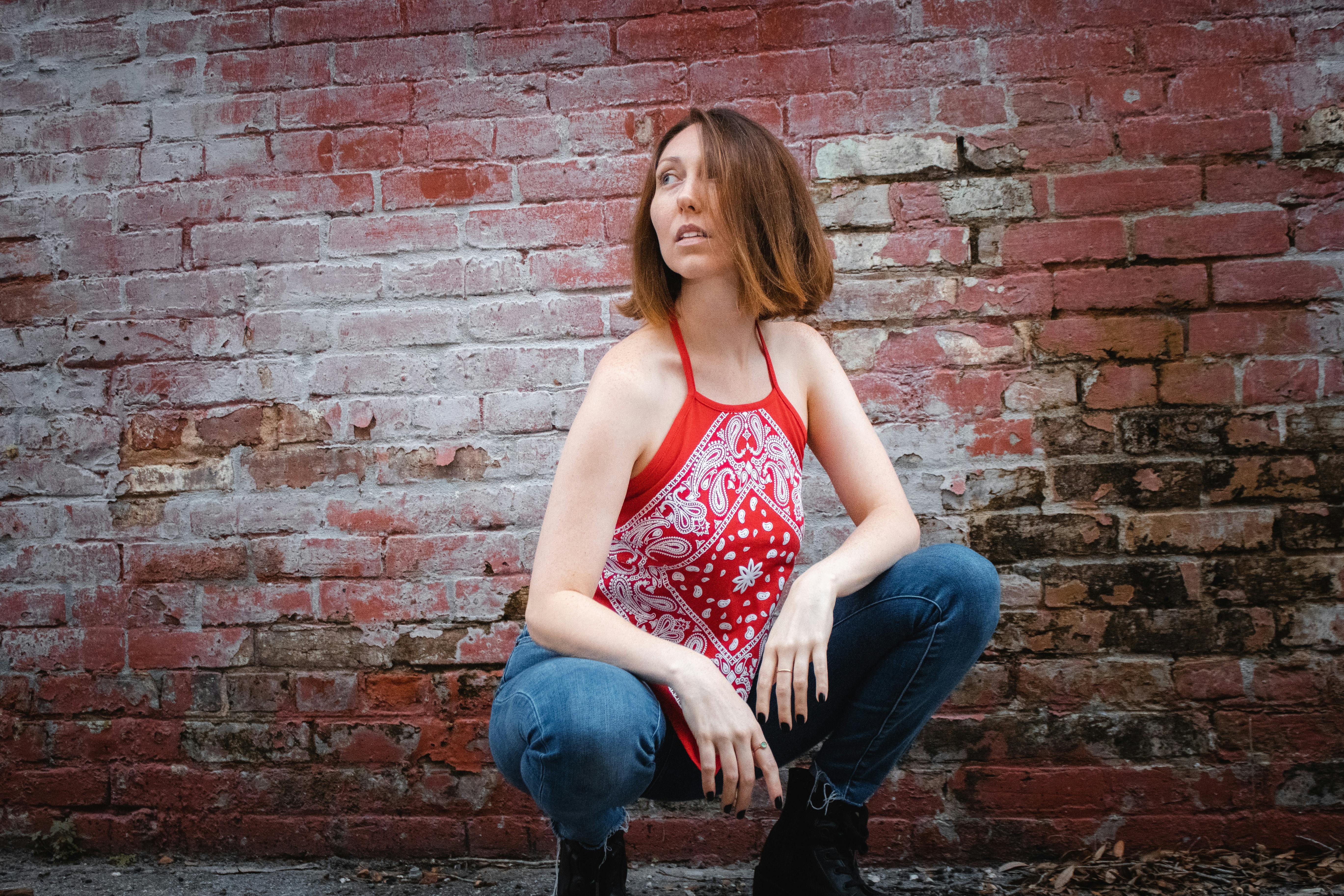 Woman Crouching and Posing by Wall · Free Stock Photo
