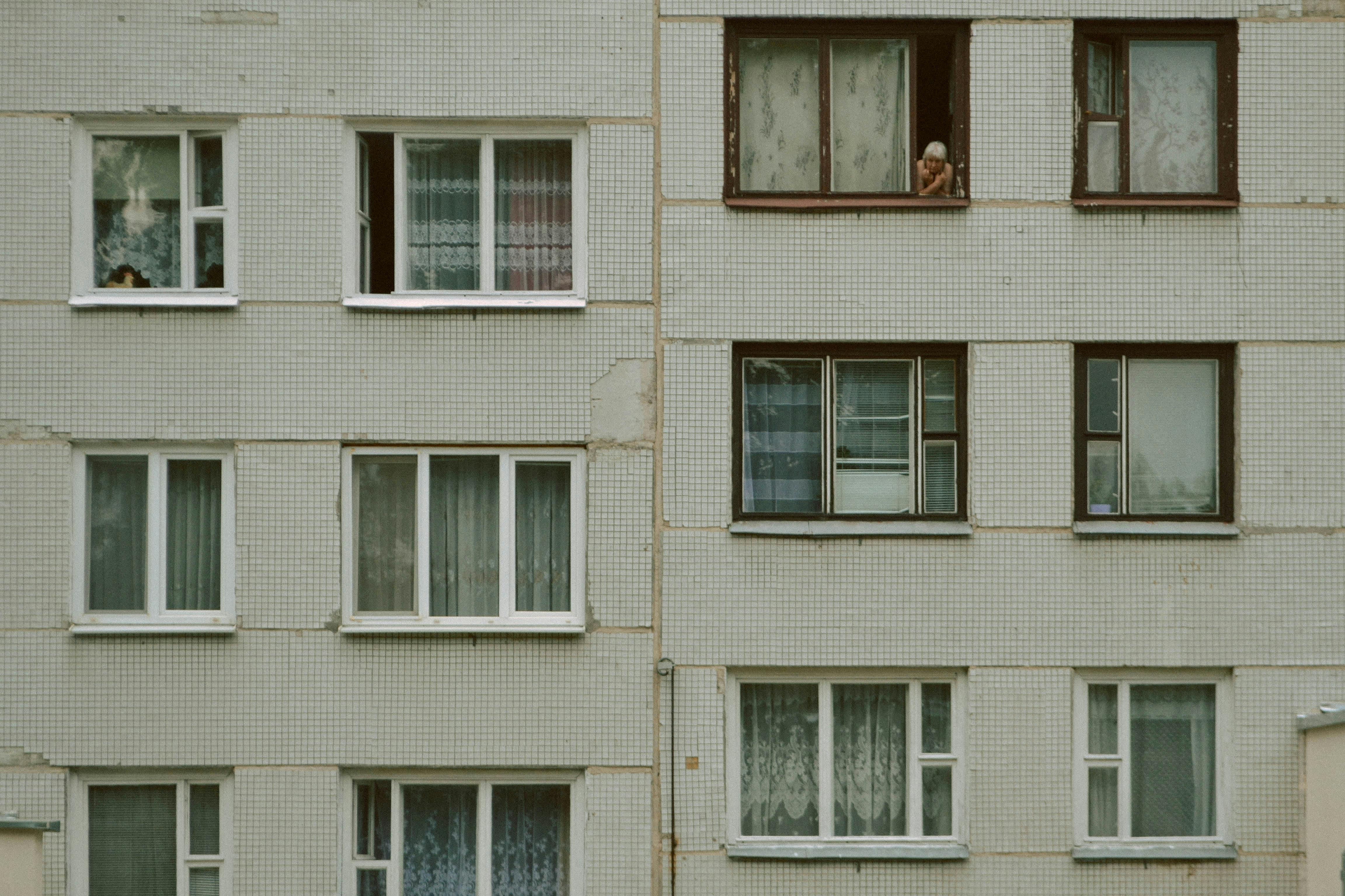 A Person Looking Out the Window on an Apartment Building · Free Stock Photo