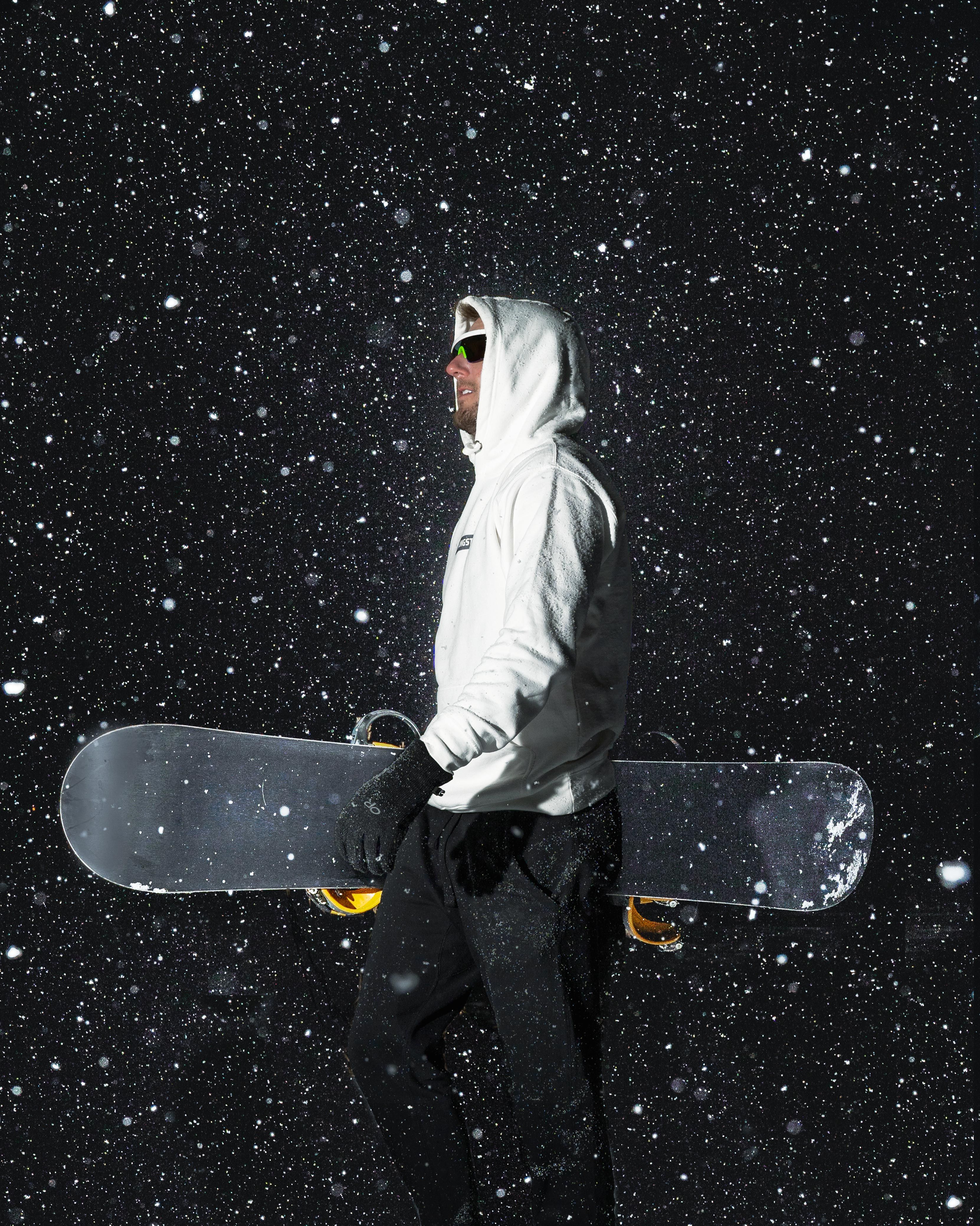Man Holding Snowboard Standing in Snowfall at Night · Free Stock Photo