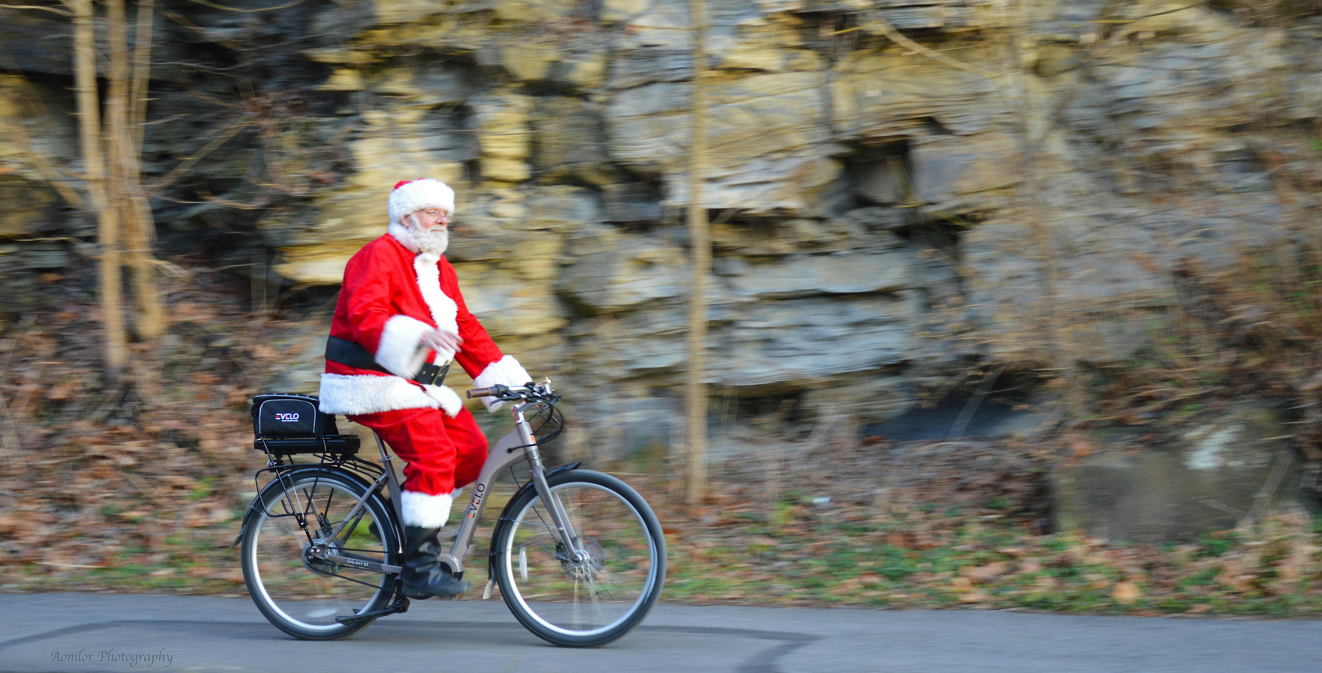 Santa Claus Riding Bicycle Past Cliff · Free Stock Photo