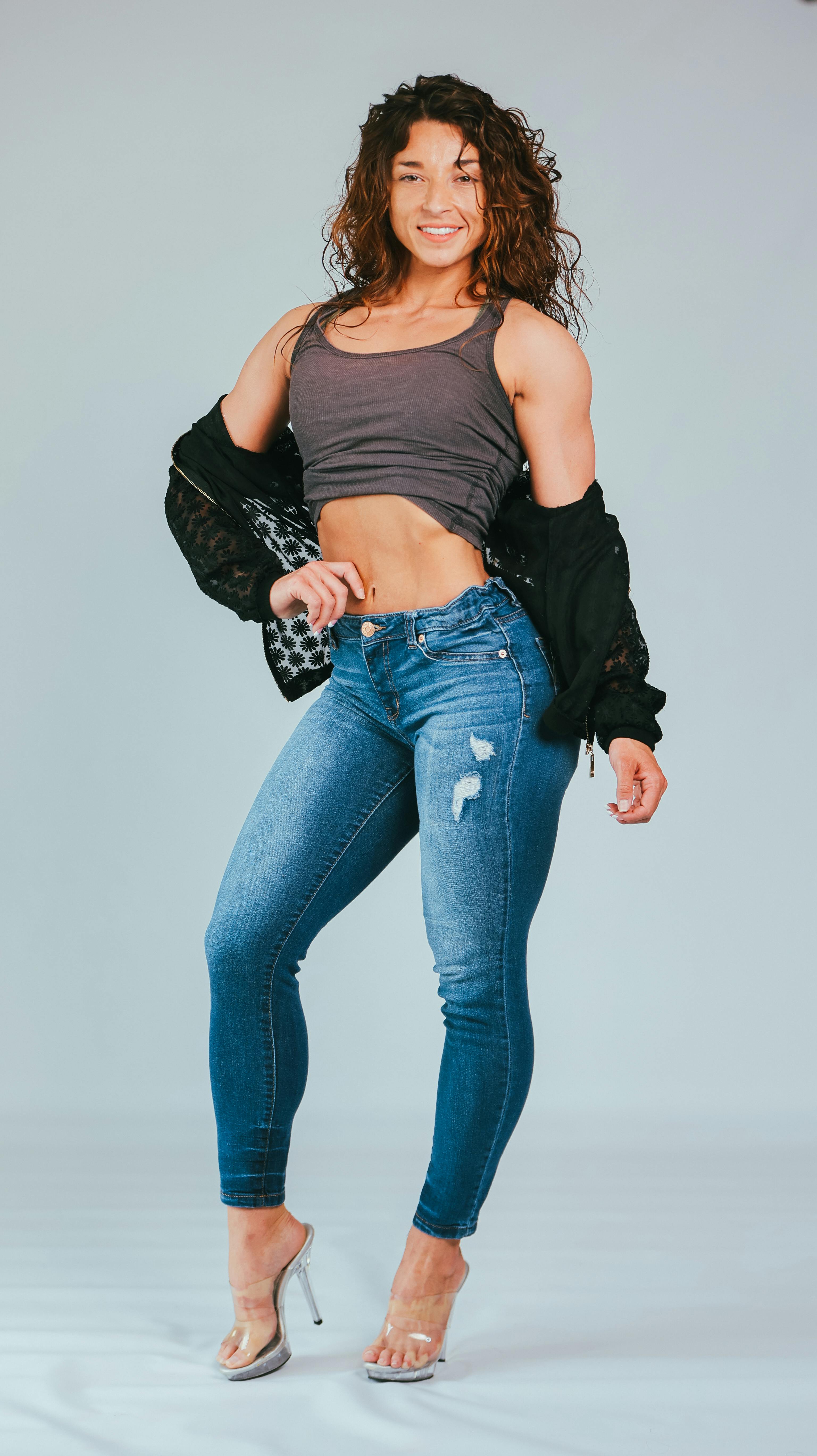 A Muscular Woman Wearing Black Jacket and Denim Jeans Posing at the ...