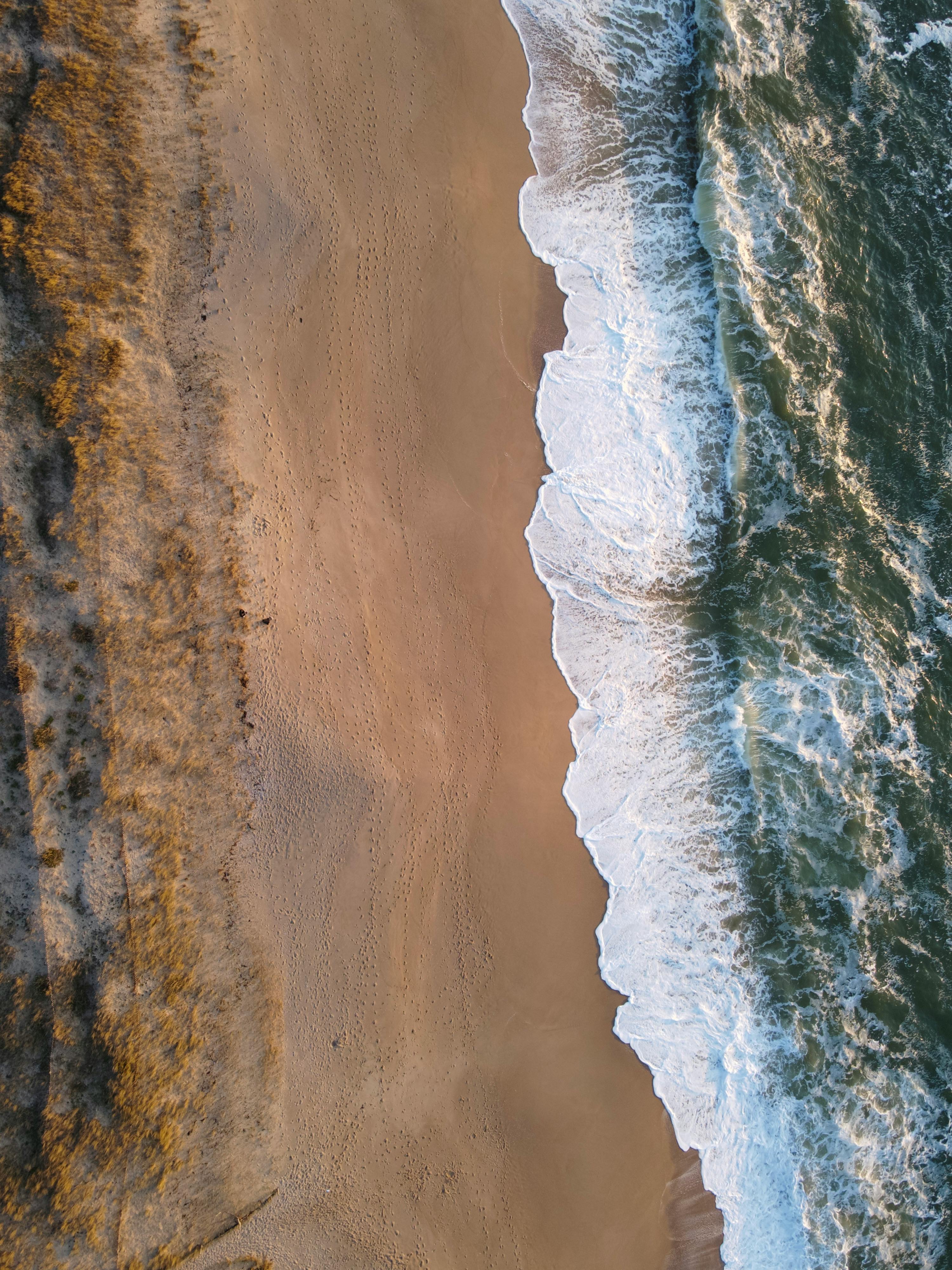 Top View Shot of Sea Waves Crashing the Sandy Shore · Free Stock Photo