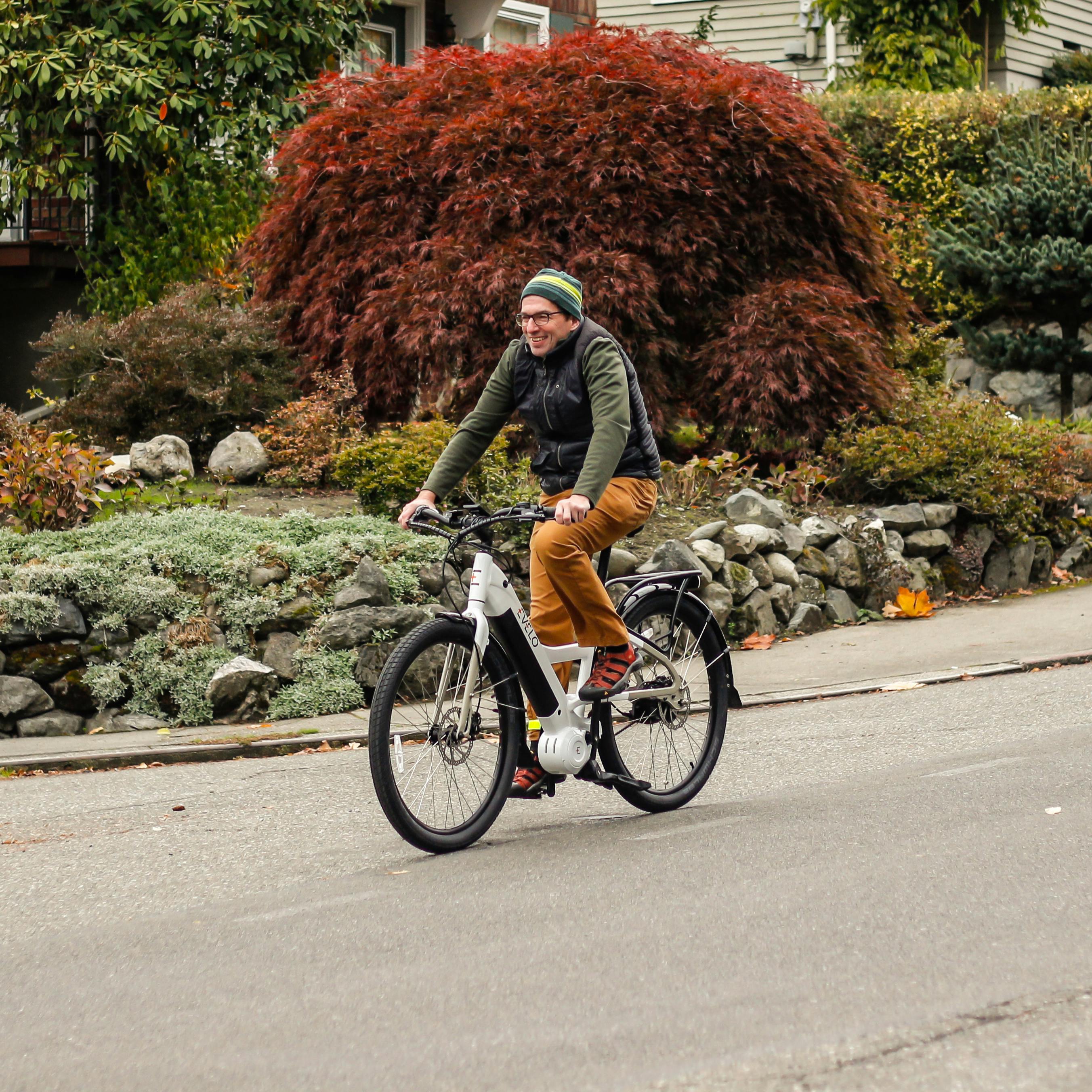 A man riding an electric bike down a street · Free Stock Photo