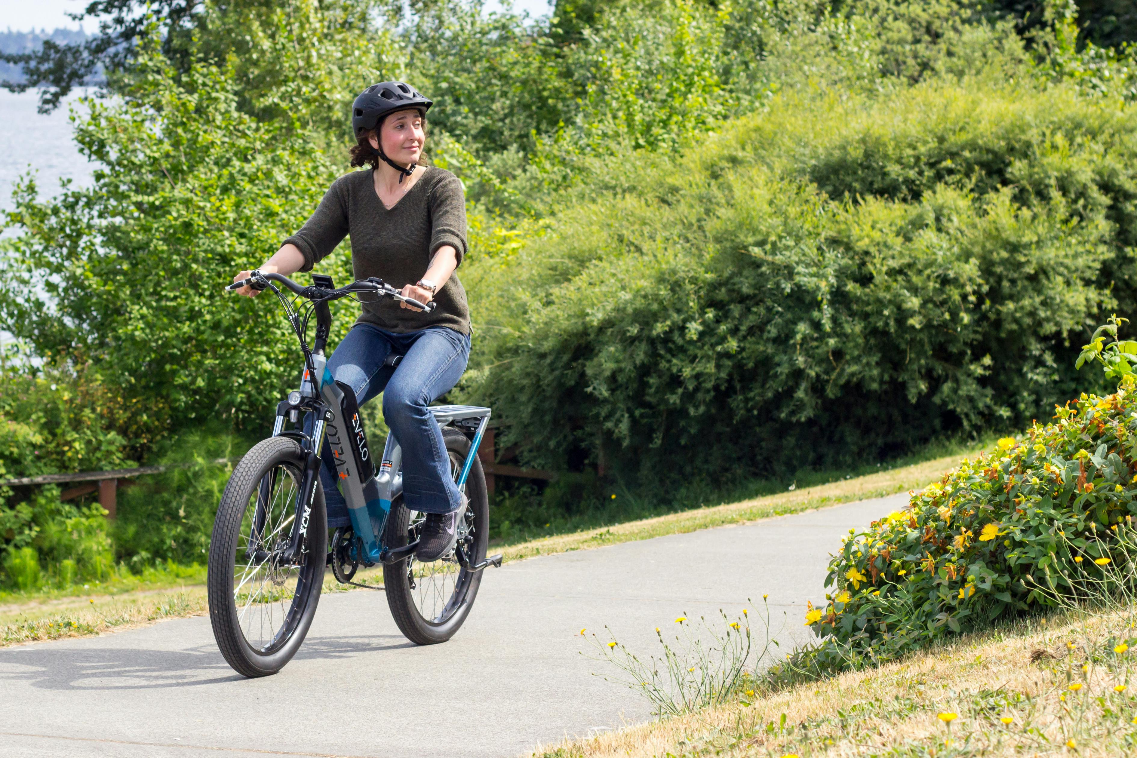 A woman riding an electric bike on a paved path · Free Stock Photo