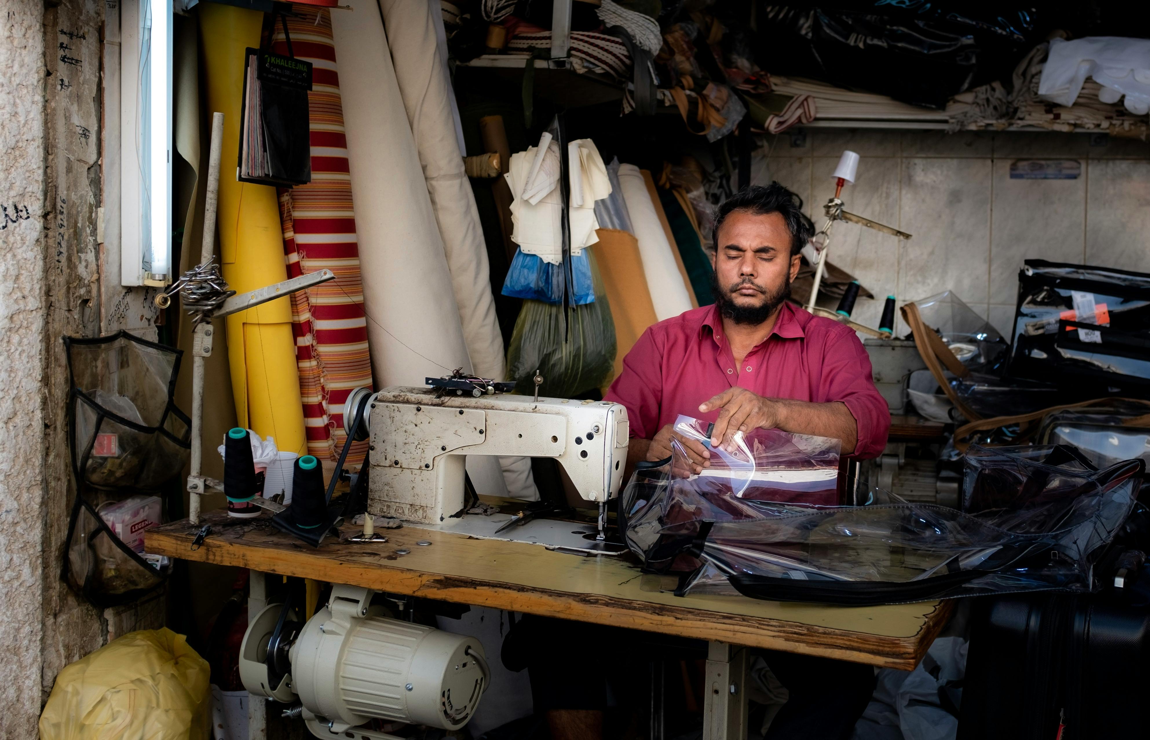 Man in Red Long Sleeve Shirt Sitting on a Sewing Machine on a Tailor ...