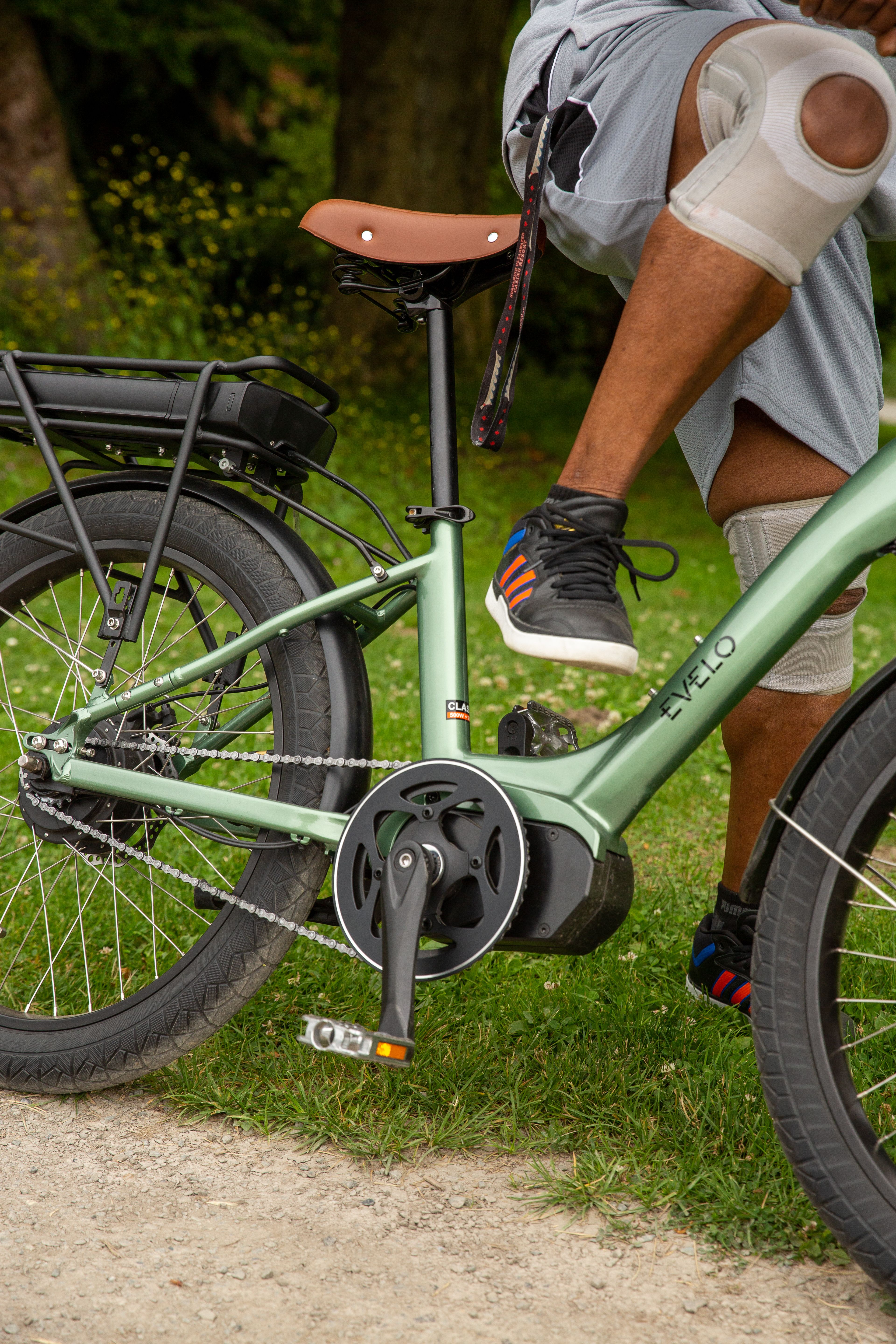 A man is riding a green bike with a knee brace · Free Stock Photo