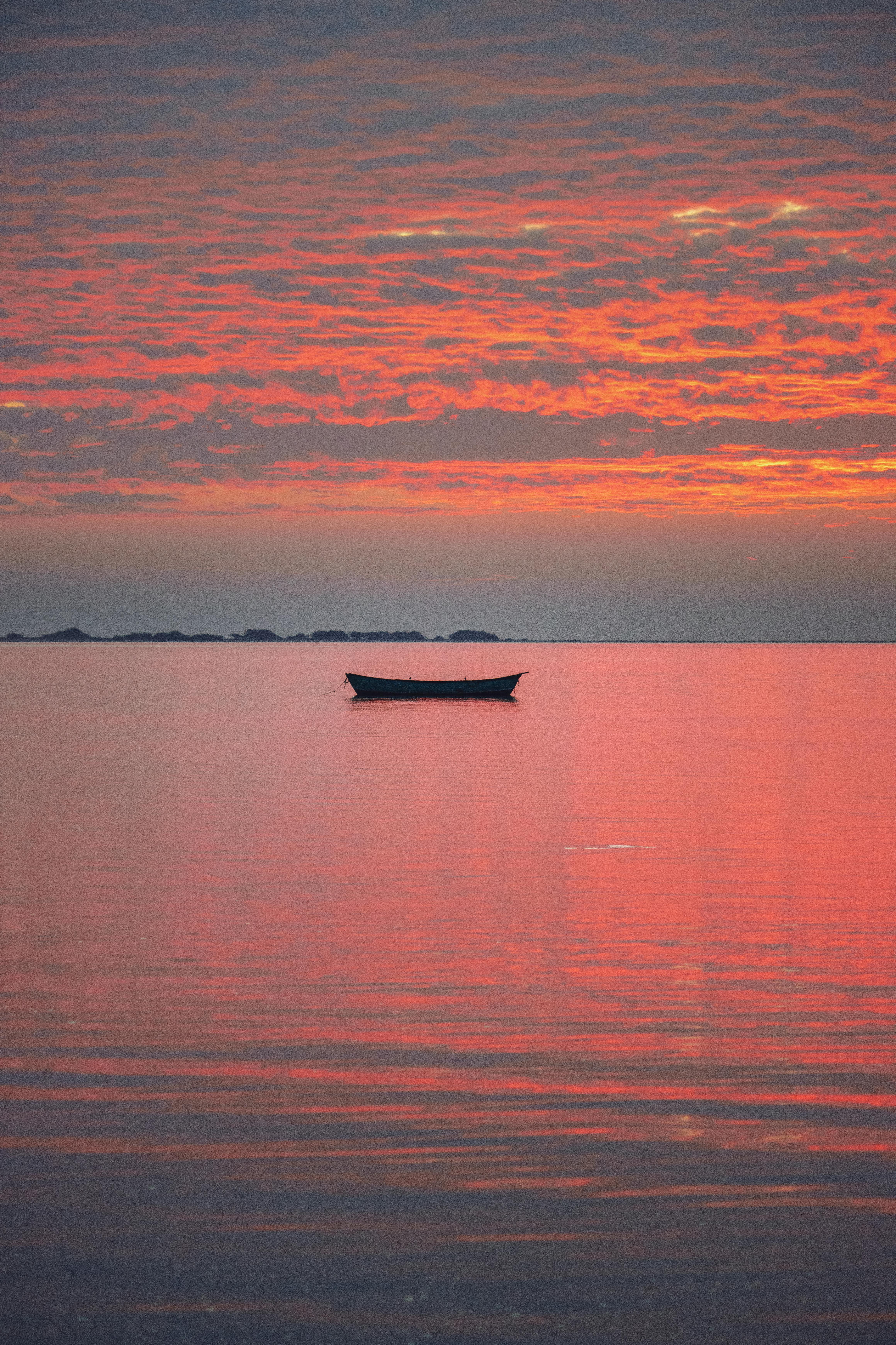 Empty Boat in Water on Dramatic Sunset · Free Stock Photo