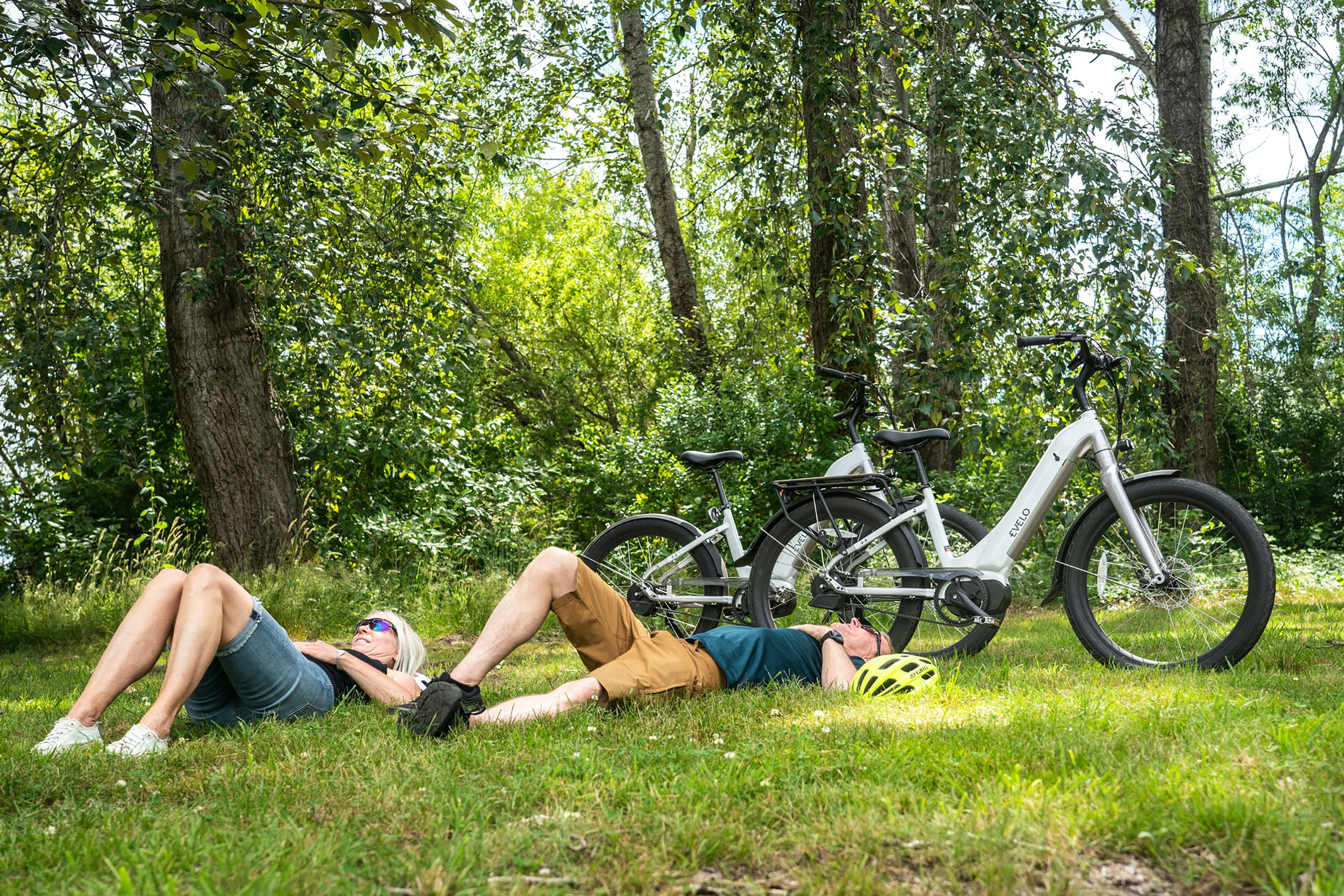 A Couple Resting on Green Grass Beside Electric Bikes · Free Stock Photo