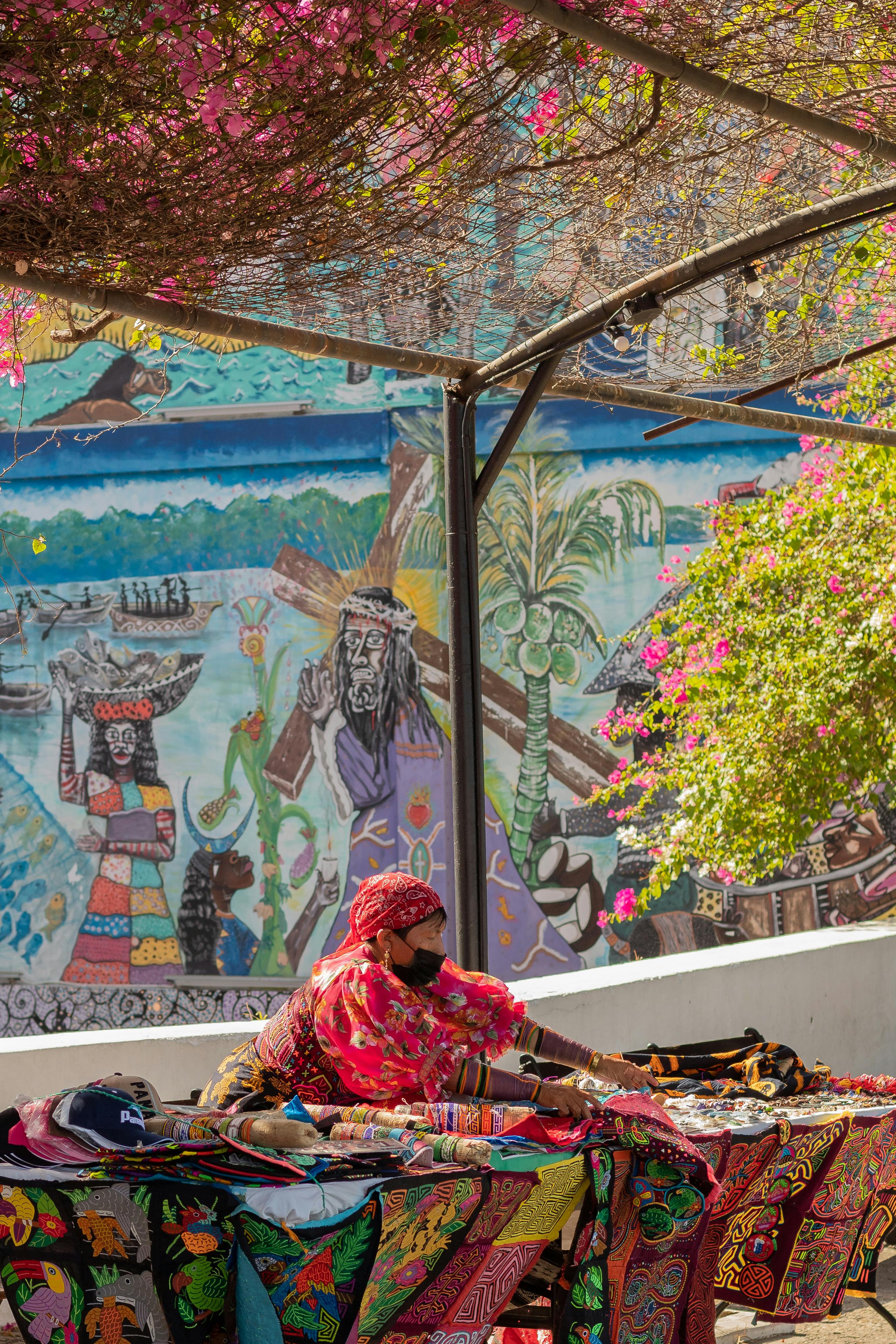 Woman Sitting by Table with Traditional Tablecloths and with Mural on ...