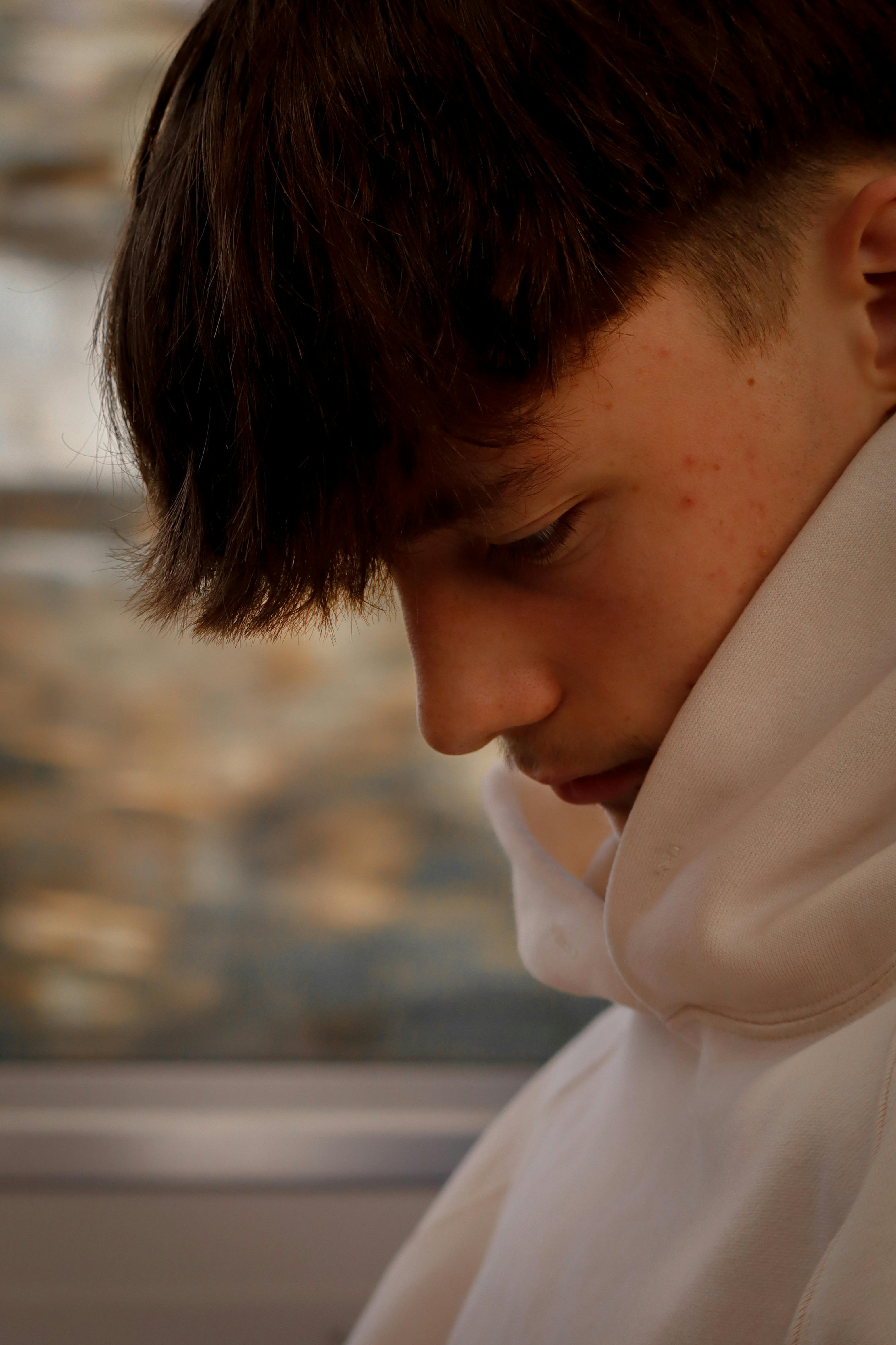 A Close-up Shot of a Man in White Hoodie Looking Down · Free Stock Photo
