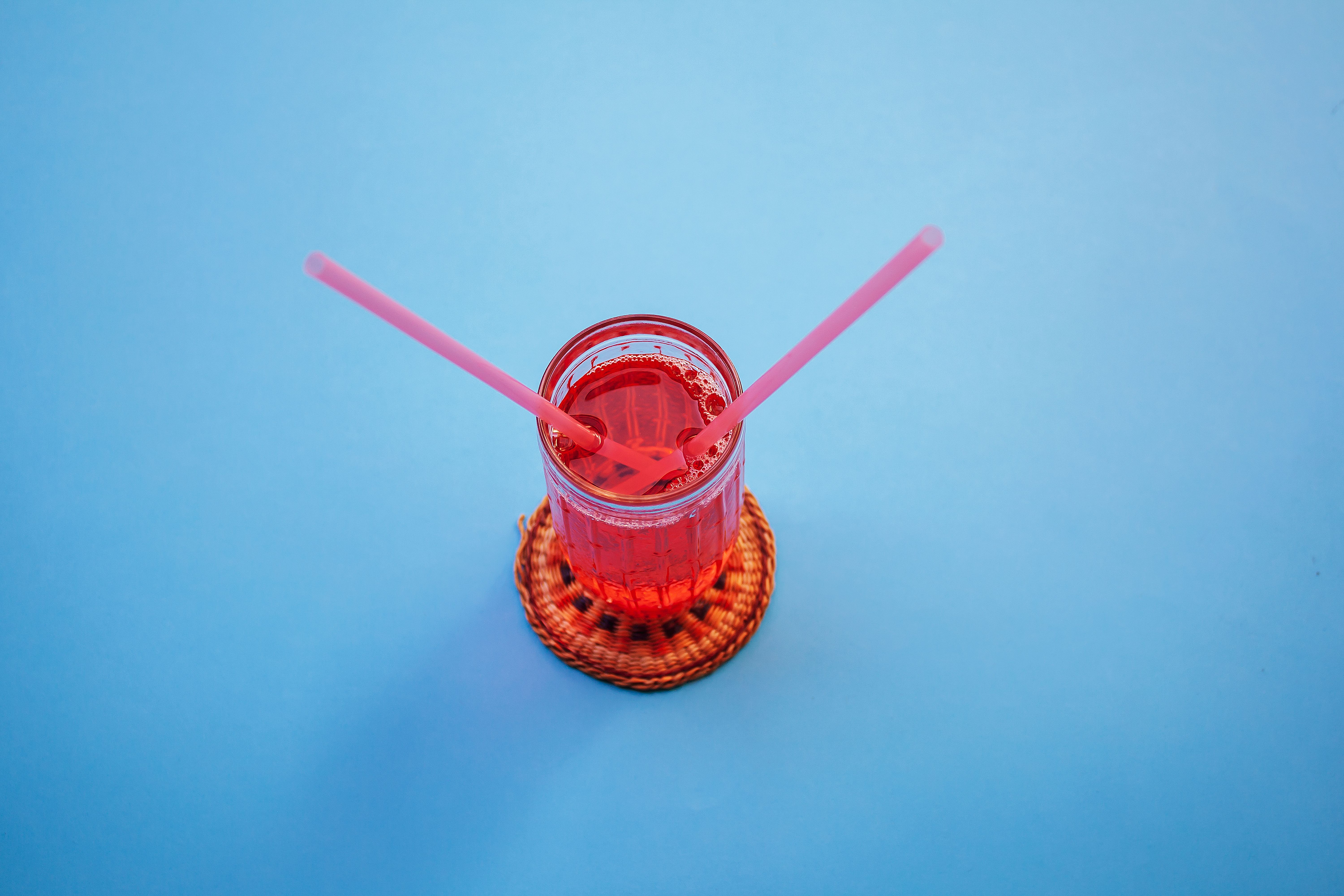 A glass of red liquid with two straws · Free Stock Photo