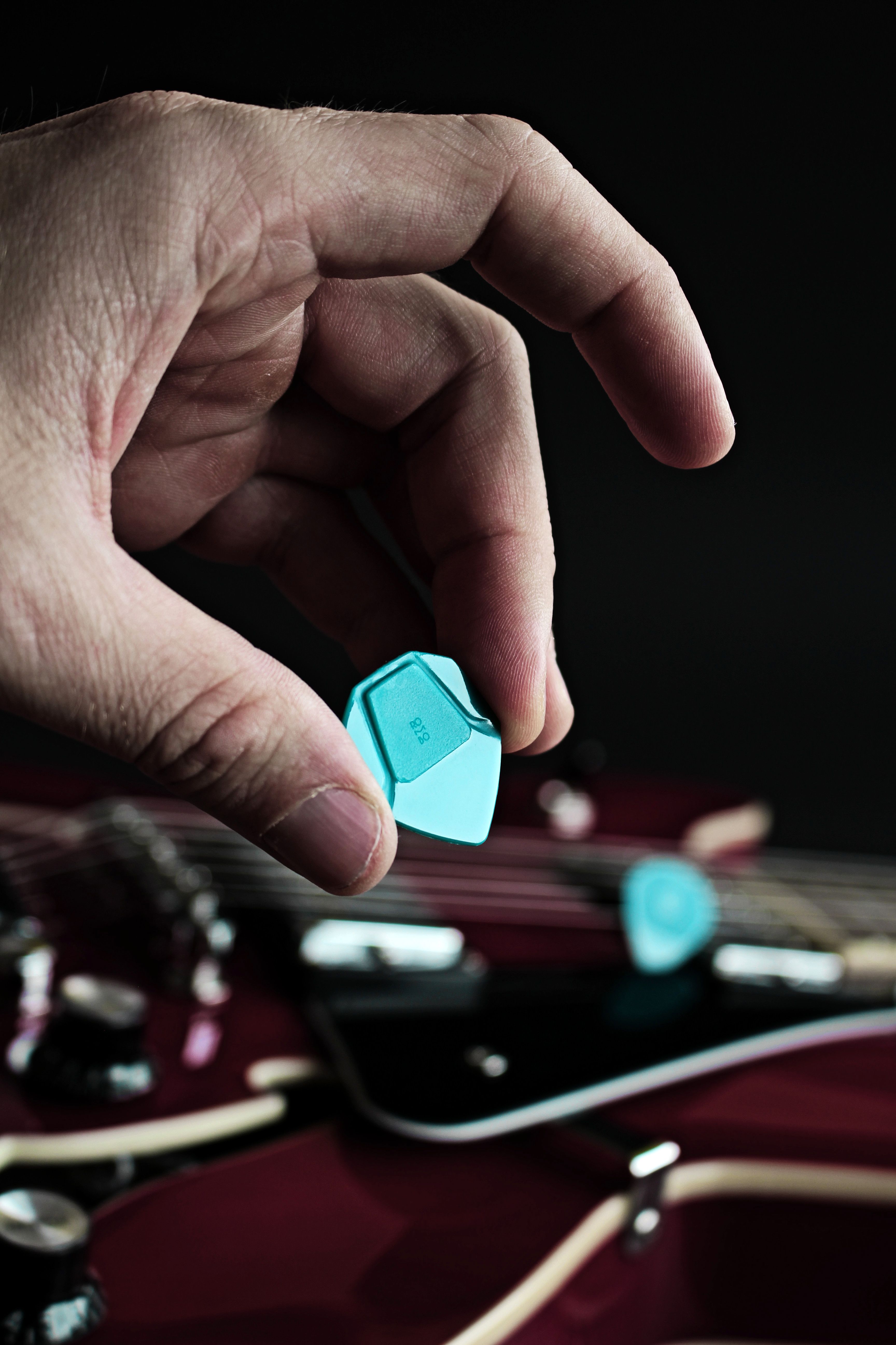 Person Holding a Guitar Pick · Free Stock Photo
