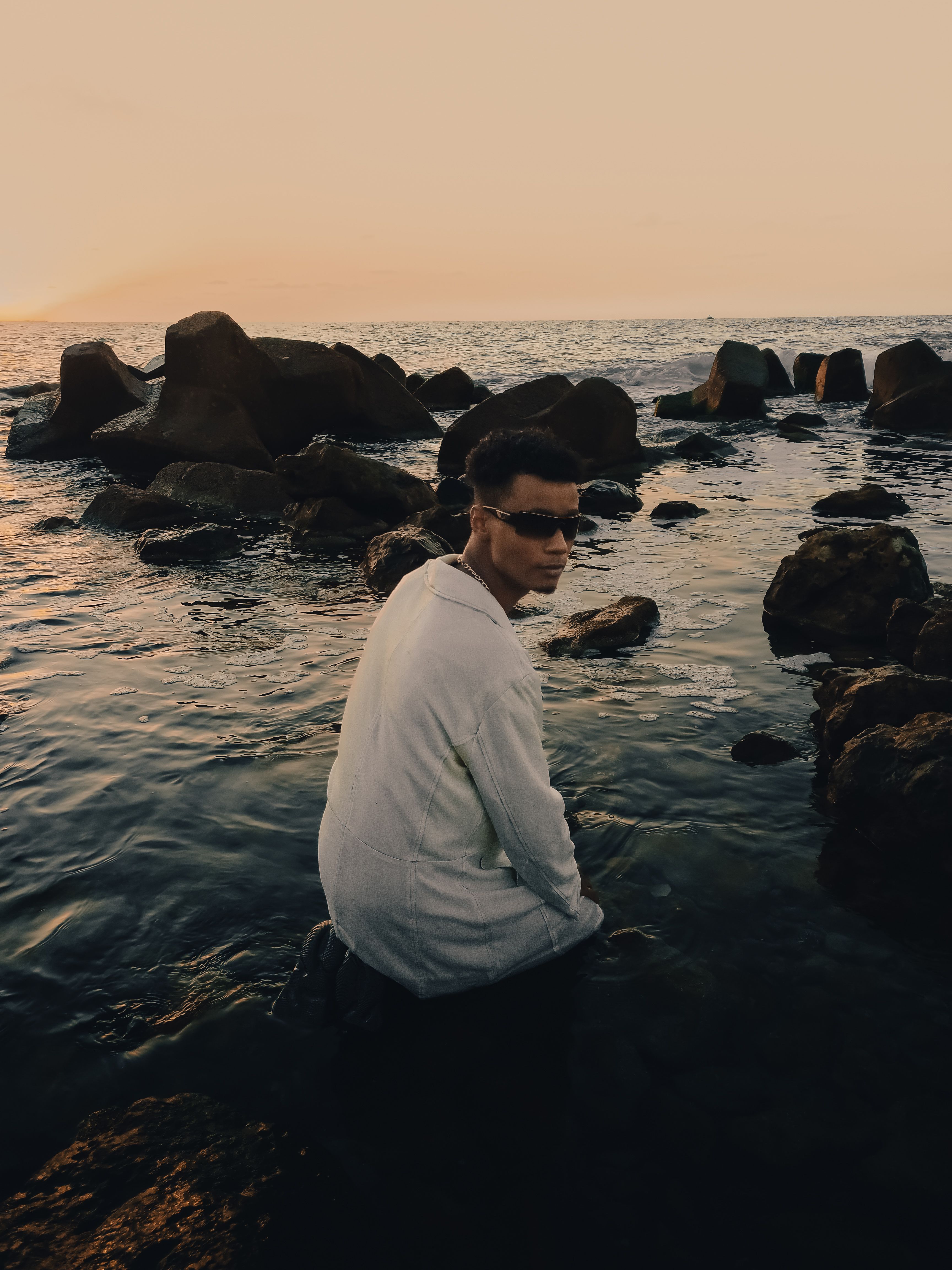 Man Posing on Rocks on Sea Shore at Dusk · Free Stock Photo