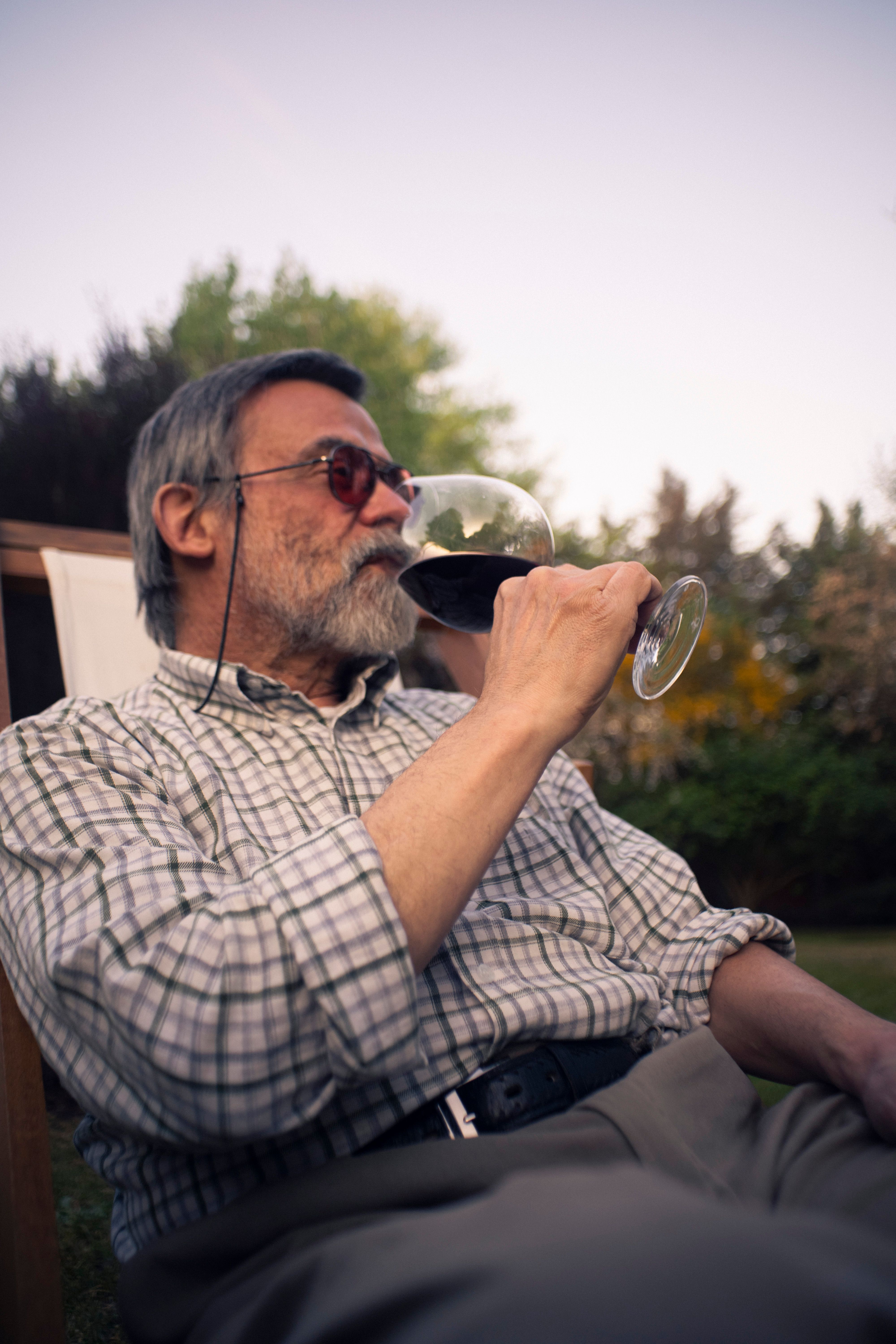 Man Sitting and Drinking Red Wine in his Yard · Free Stock Photo