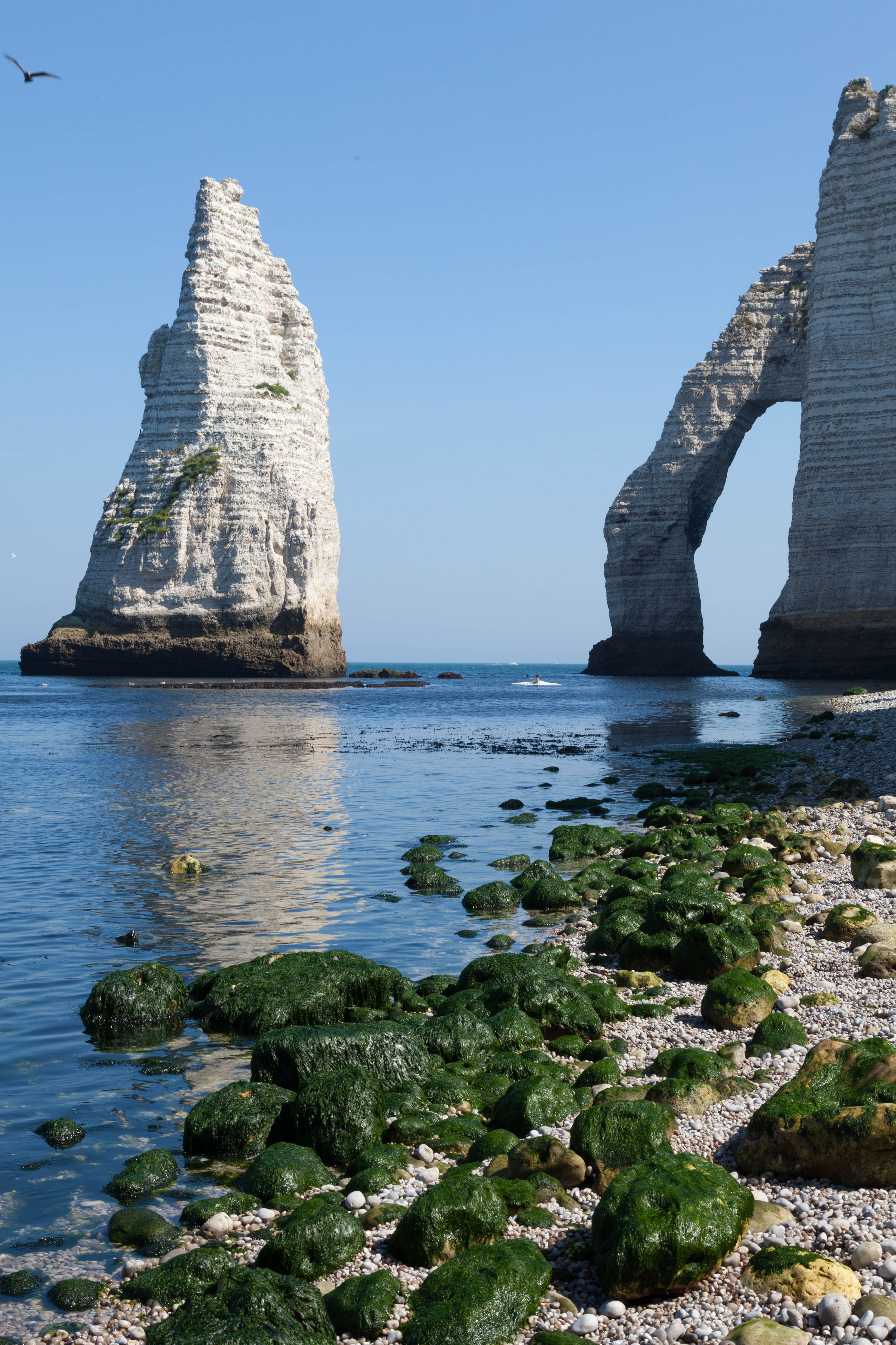 Gray Rock Formation on Body of Water Under Blue Sky · Free Stock Photo