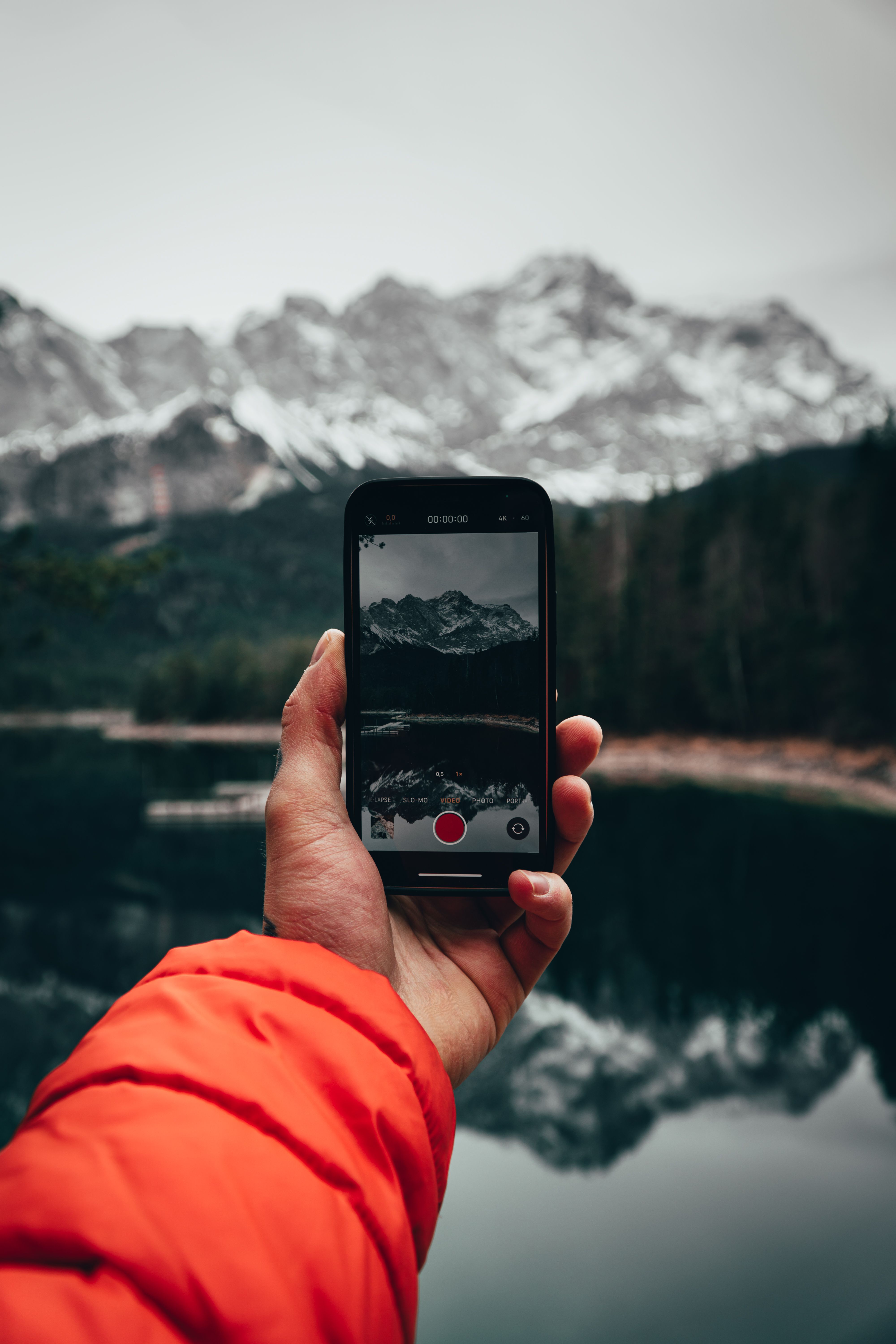 A person holding up a cell phone to take a picture of a lake · Free ...
