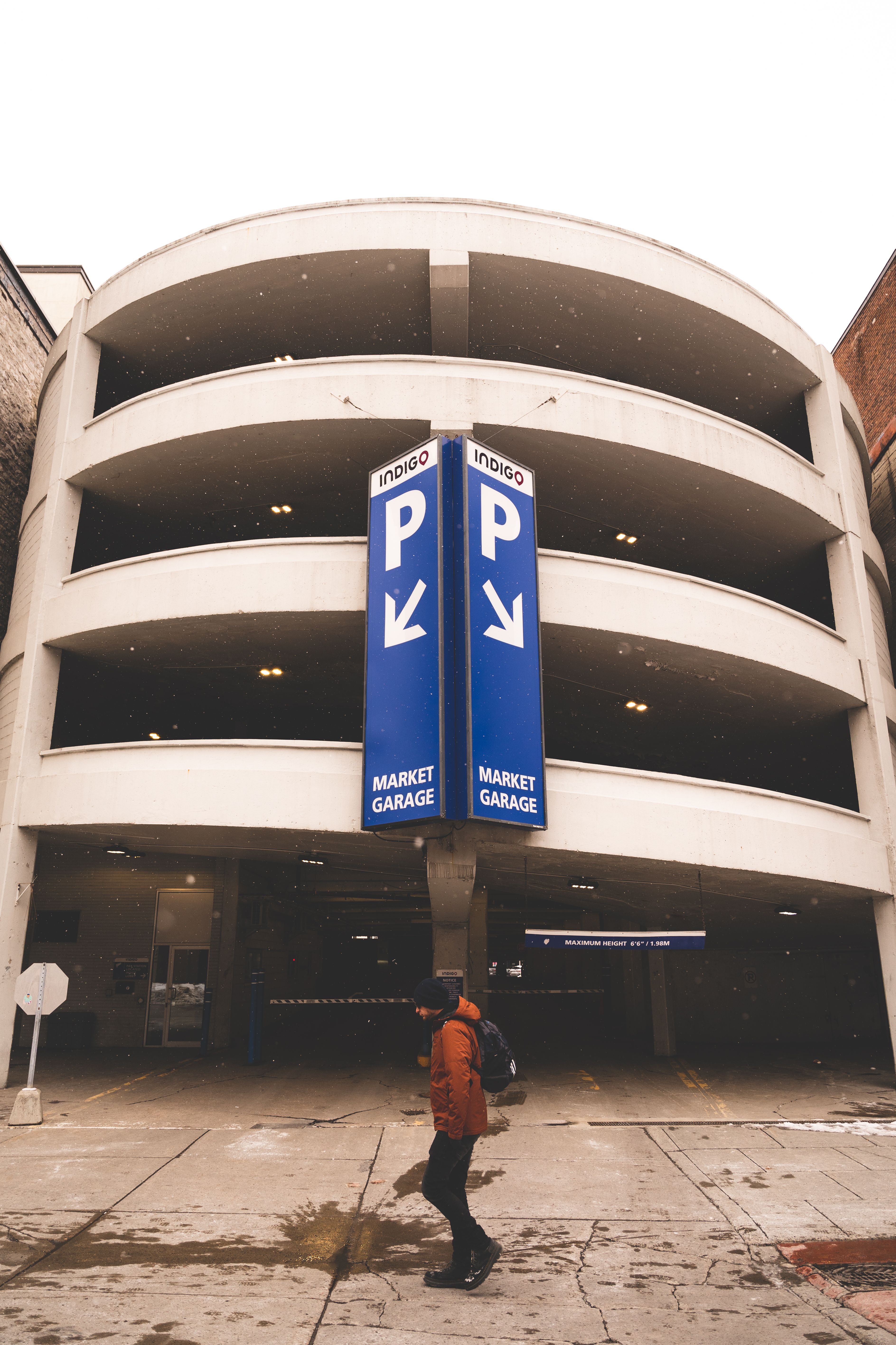 A woman walking past a parking garage with a sign · Free Stock Photo