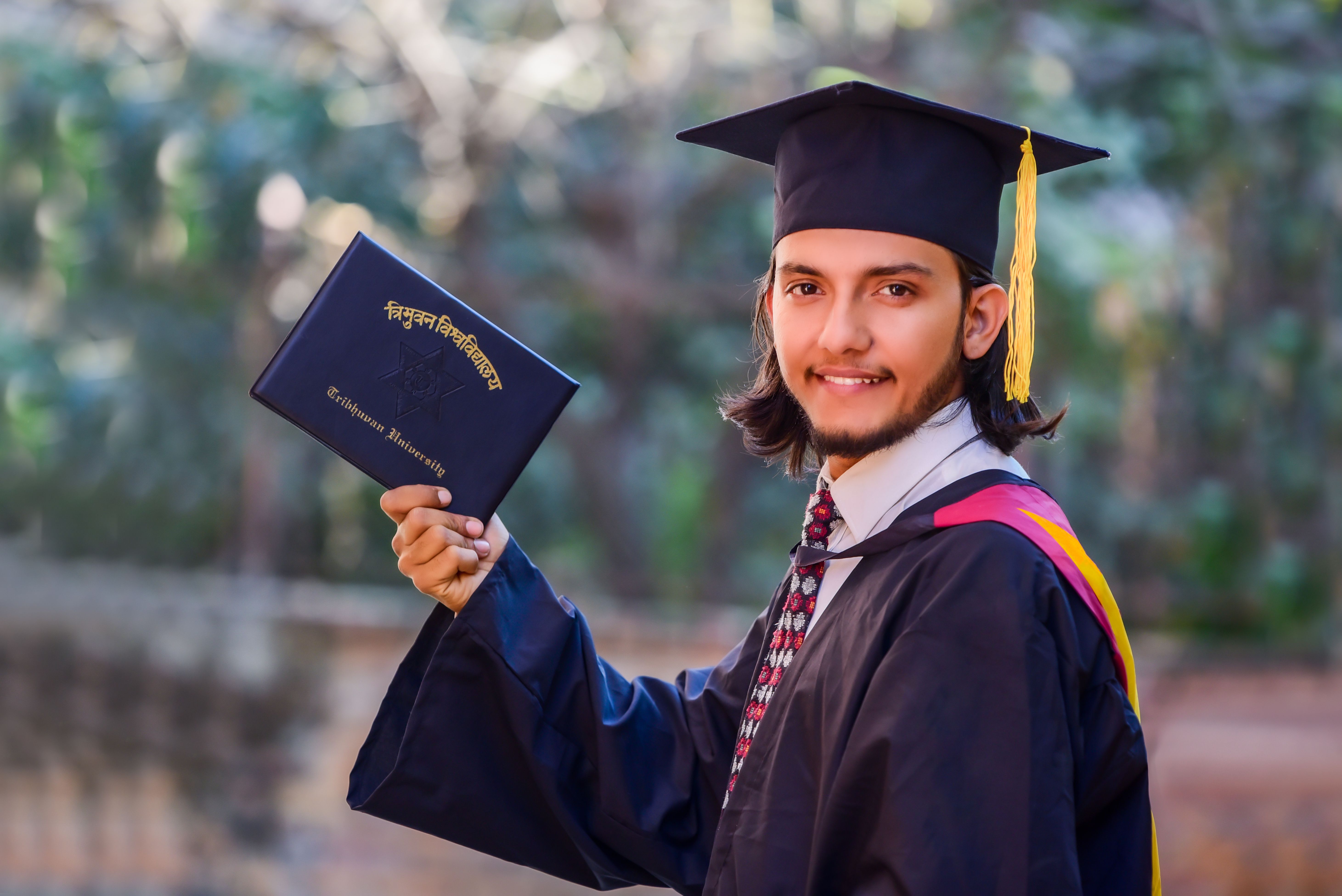 Graduate in Hijab and Gown Holding Academic Hat near Walls of Anitkabir ...