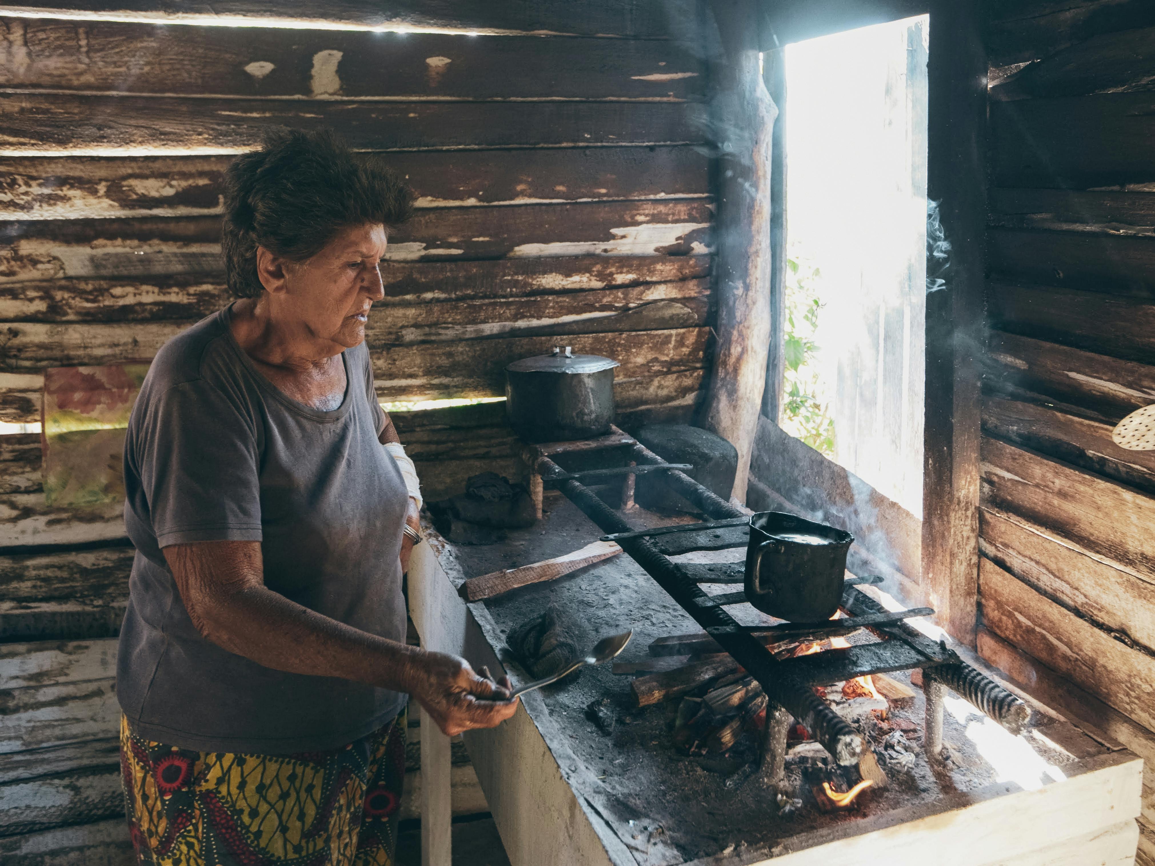 Woman Cooking on Fire in Wooden Shack · Free Stock Photo