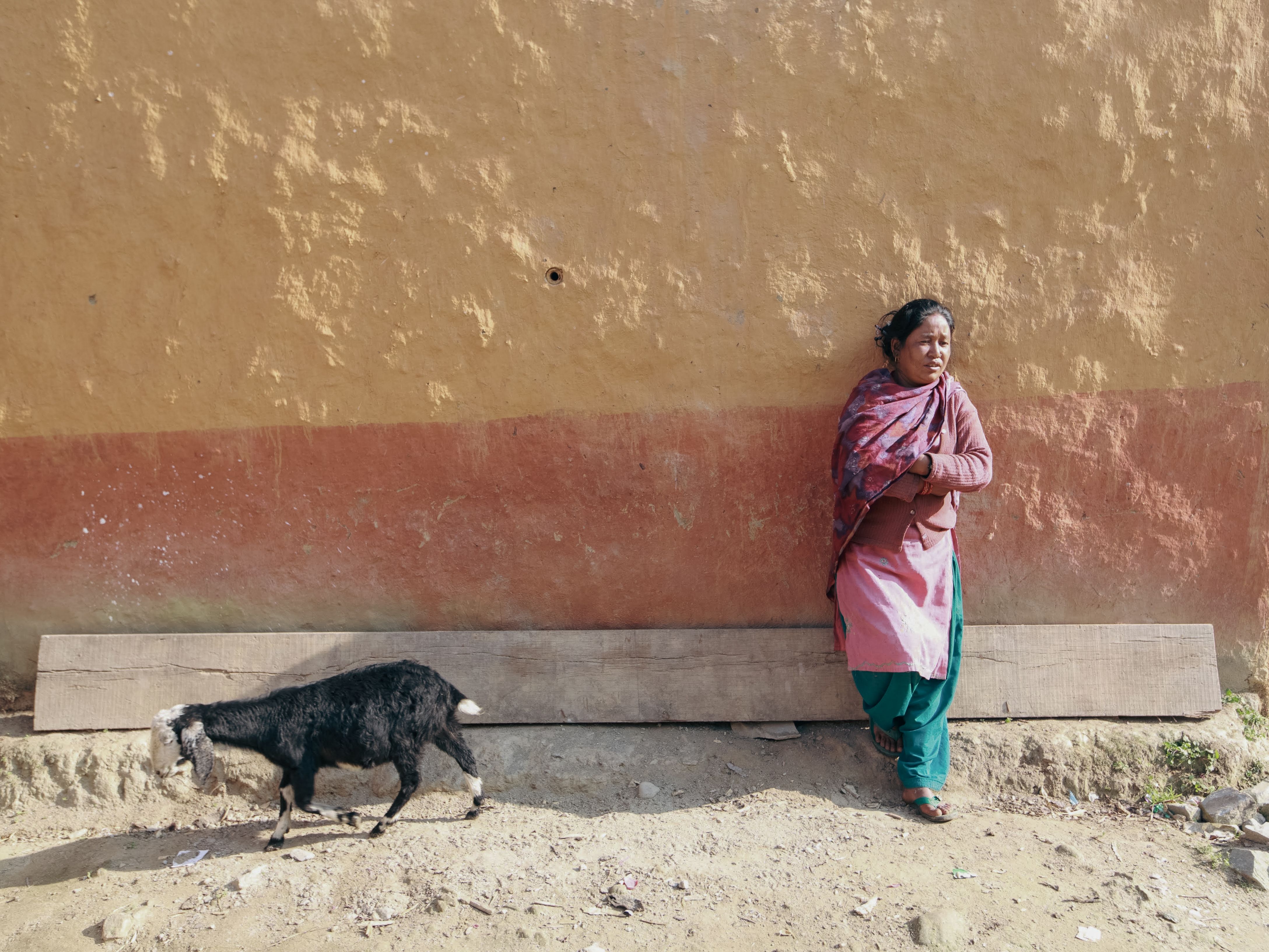 Village Woman Standing and Leaning against a Building · Free Stock Photo