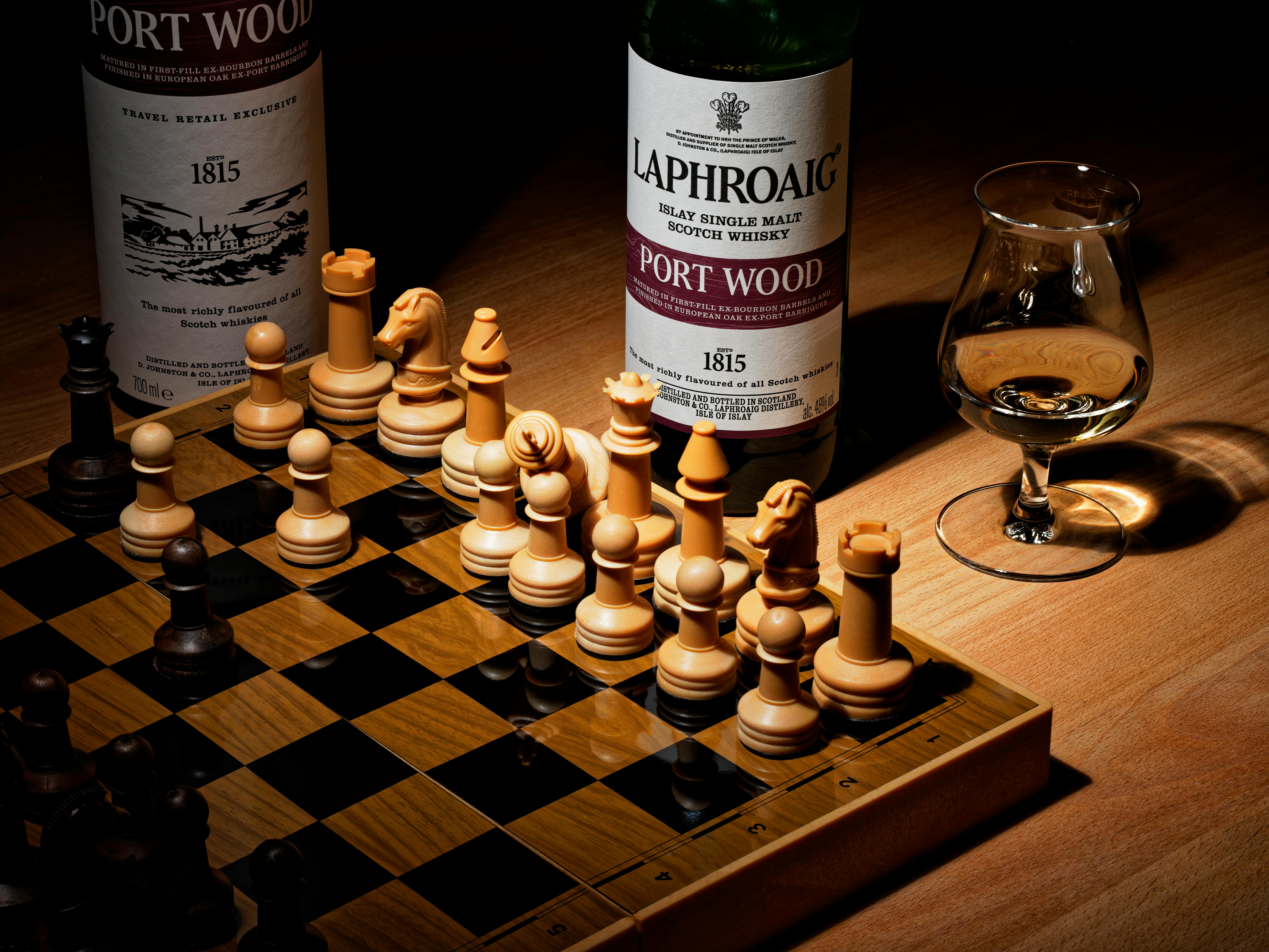 A Chess Board and Liquor Bottles on Wooden Table · Free Stock Photo