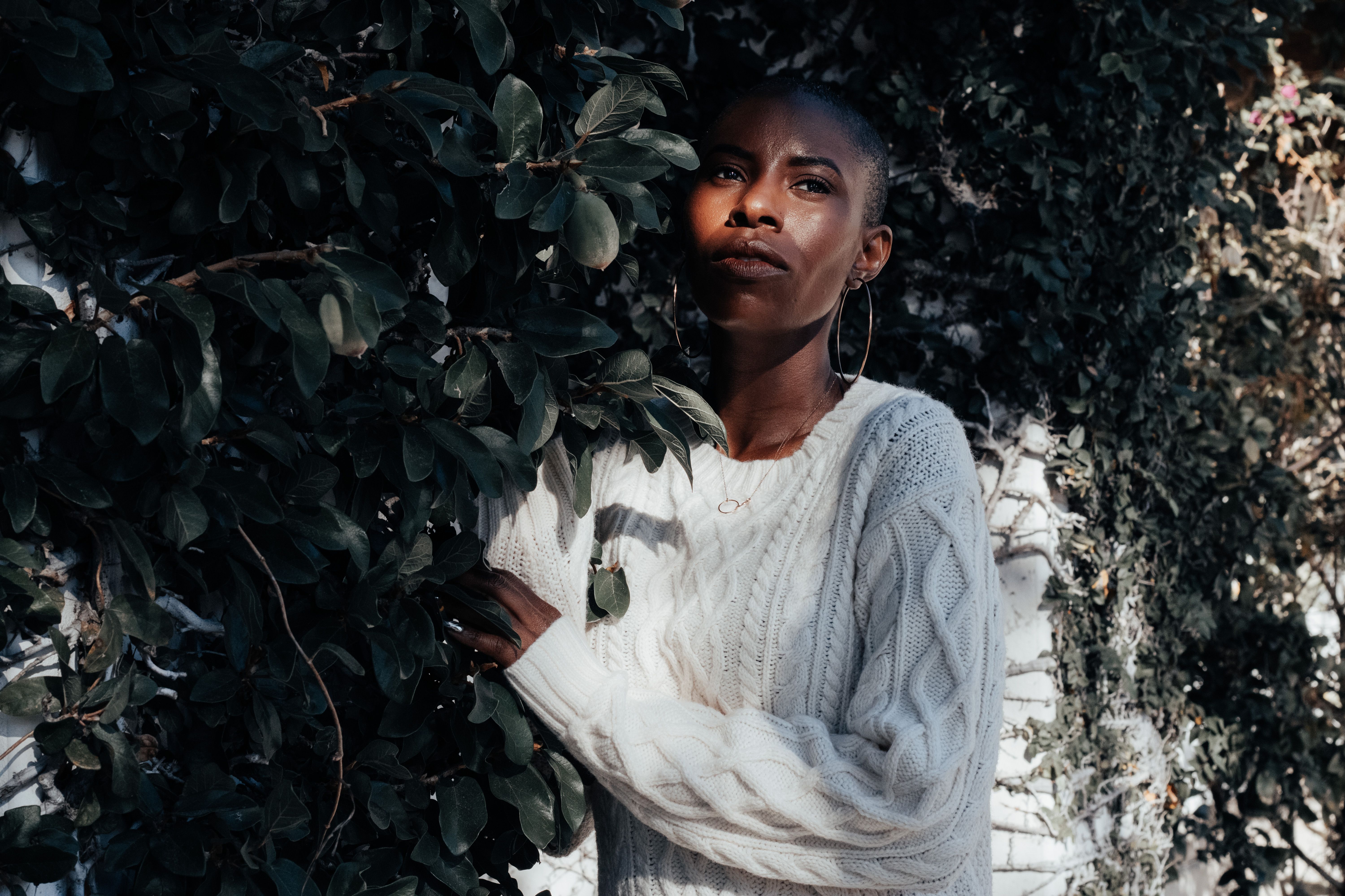 Woman in Knit Sweater with Hoop Earrings Standing Beside a Tree · Free ...