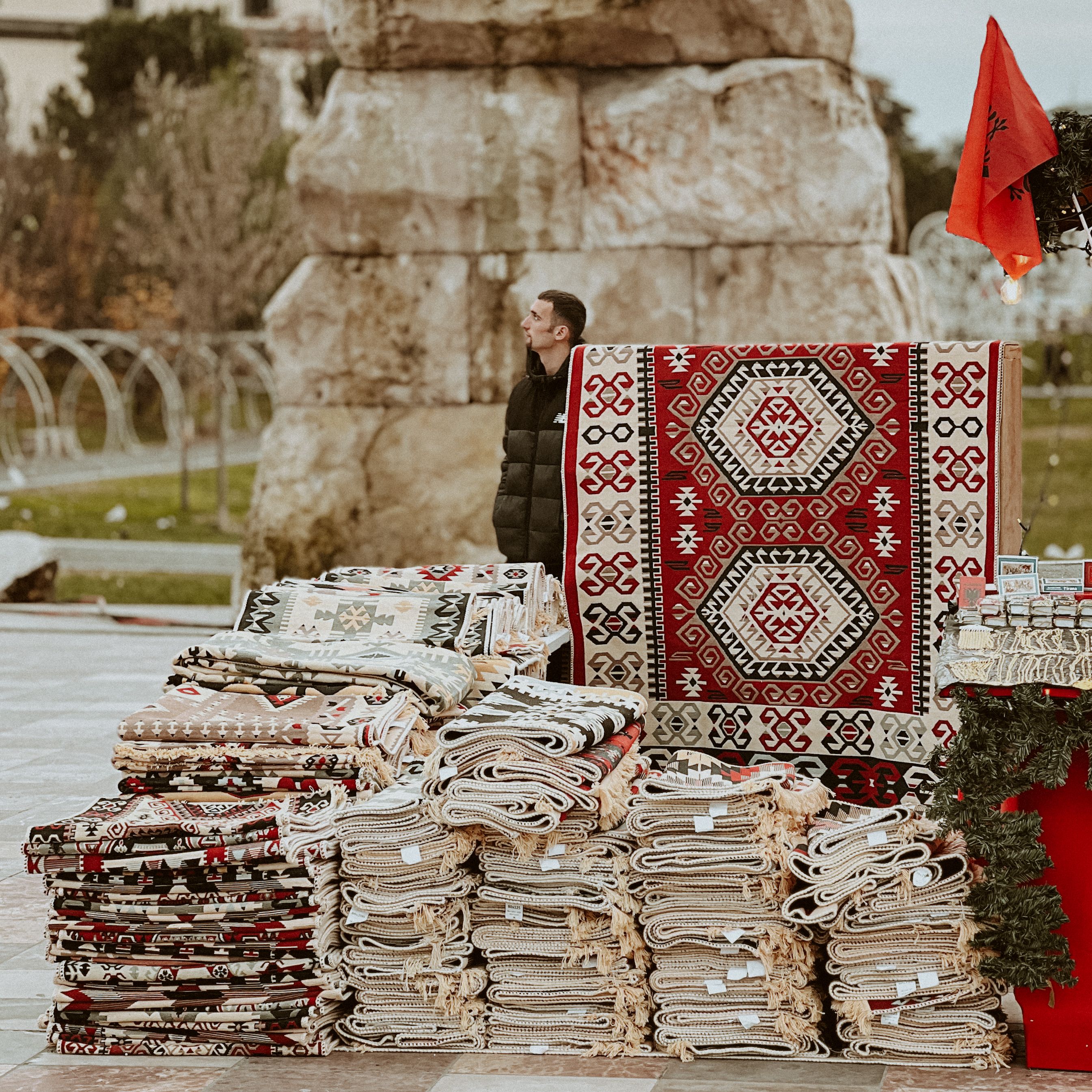A man is standing in front of a pile of rugs · Free Stock Photo
