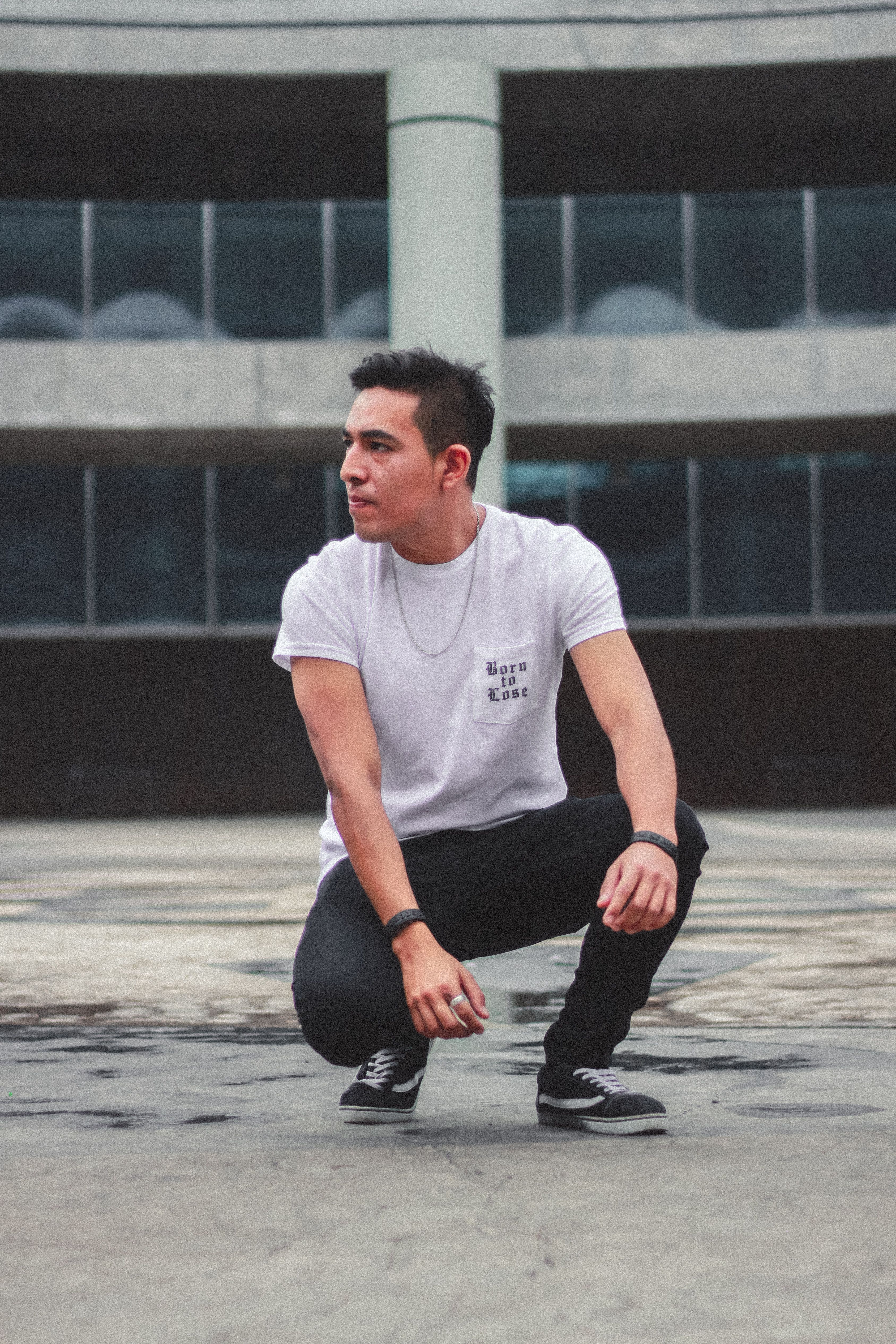 A man crouching down in front of a building · Free Stock Photo
