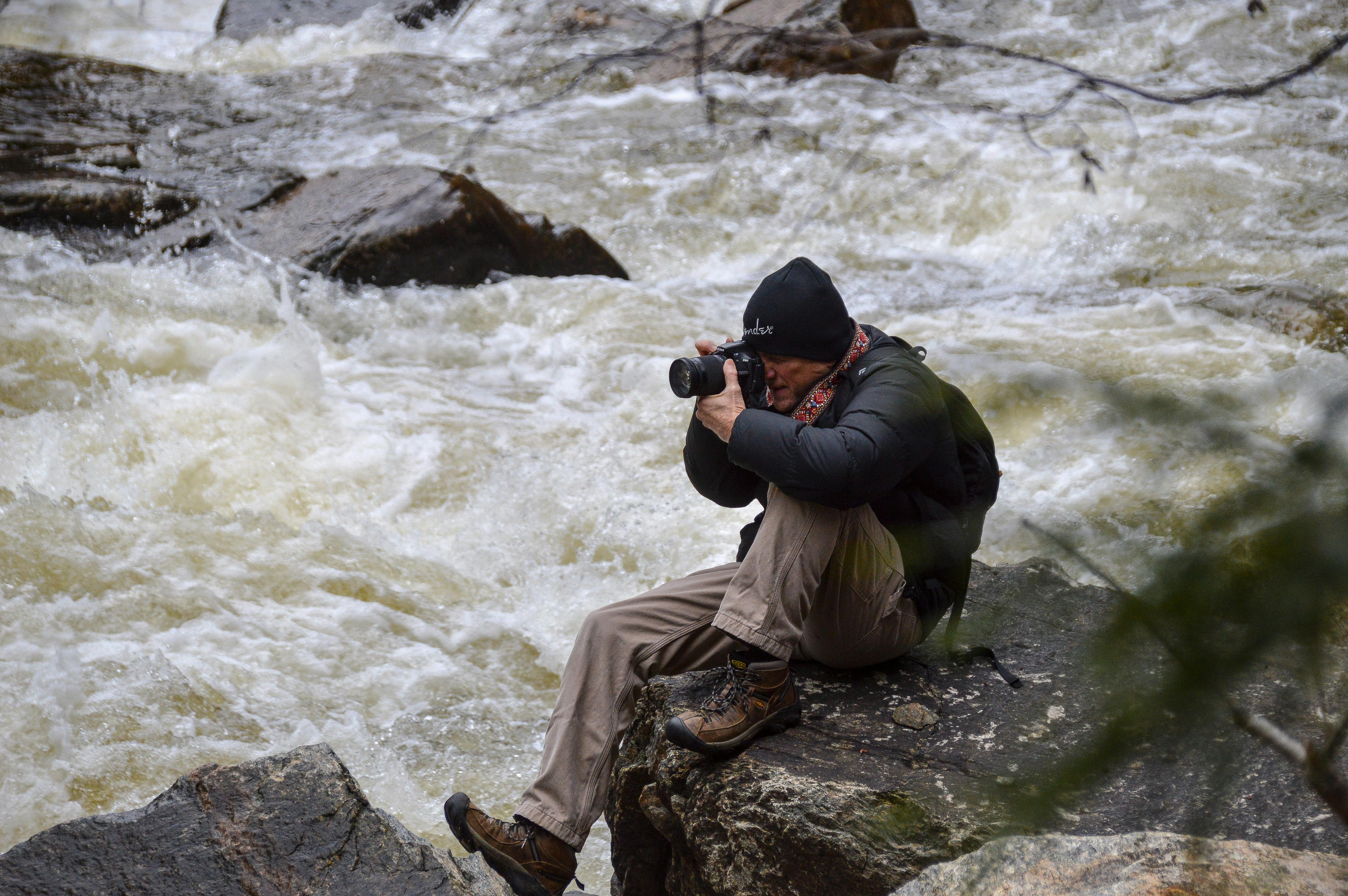 Man Sitting on Boulder While Taking Photo with a Camera · Free Stock Photo