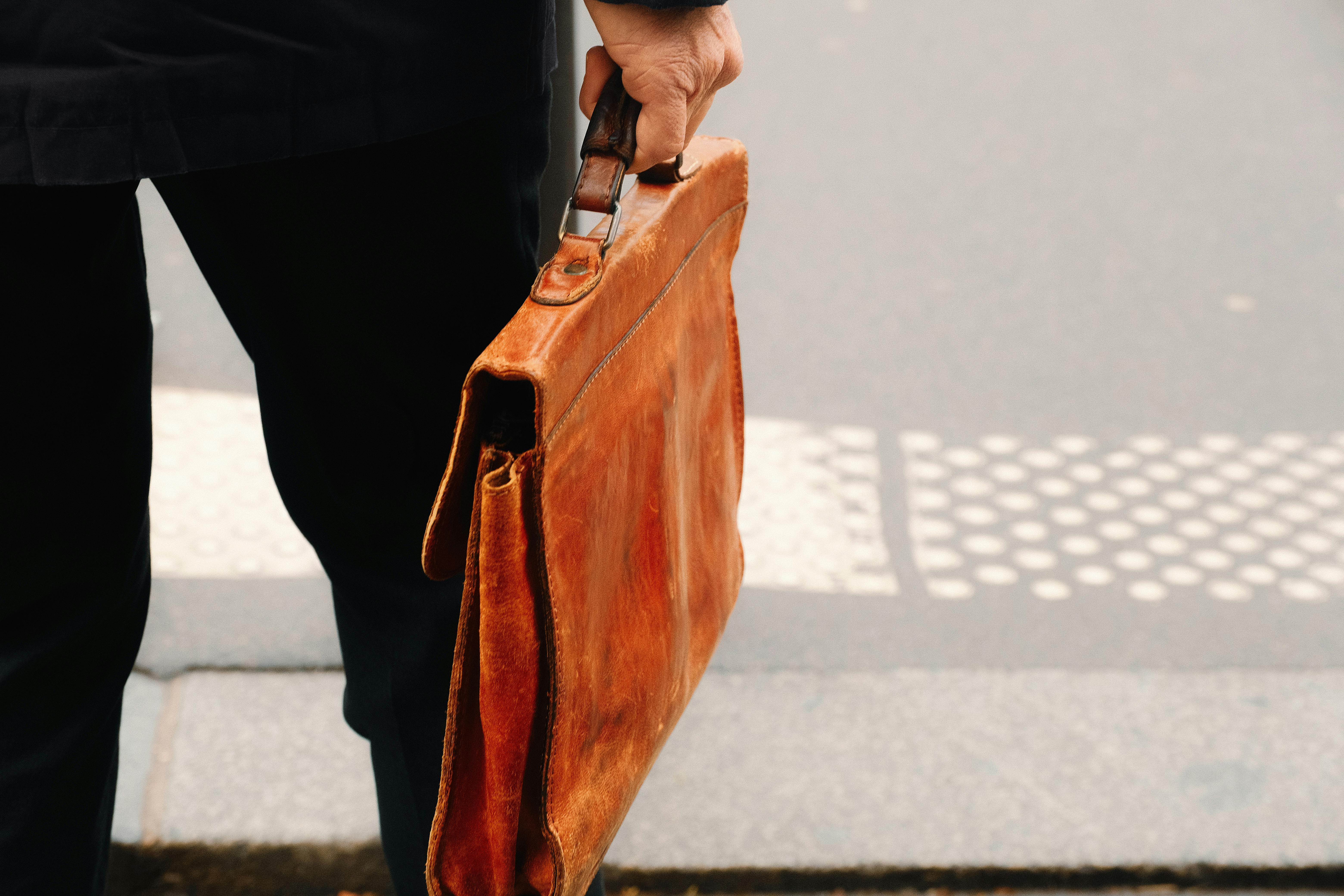 A Person's Hand Holding a Leather Briefcase · Free Stock Photo
