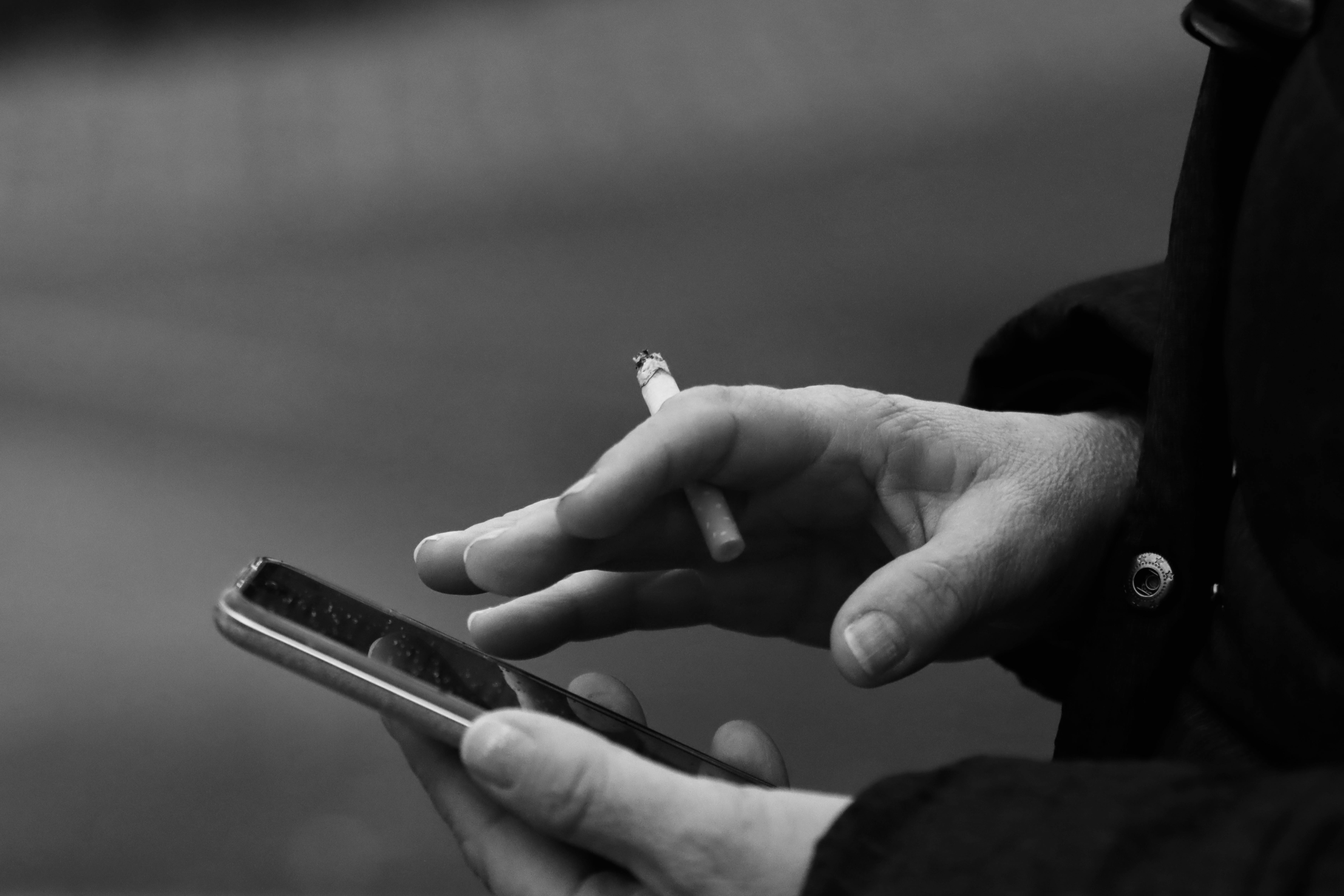 Hands Holding Cigarette and Smartphone · Free Stock Photo