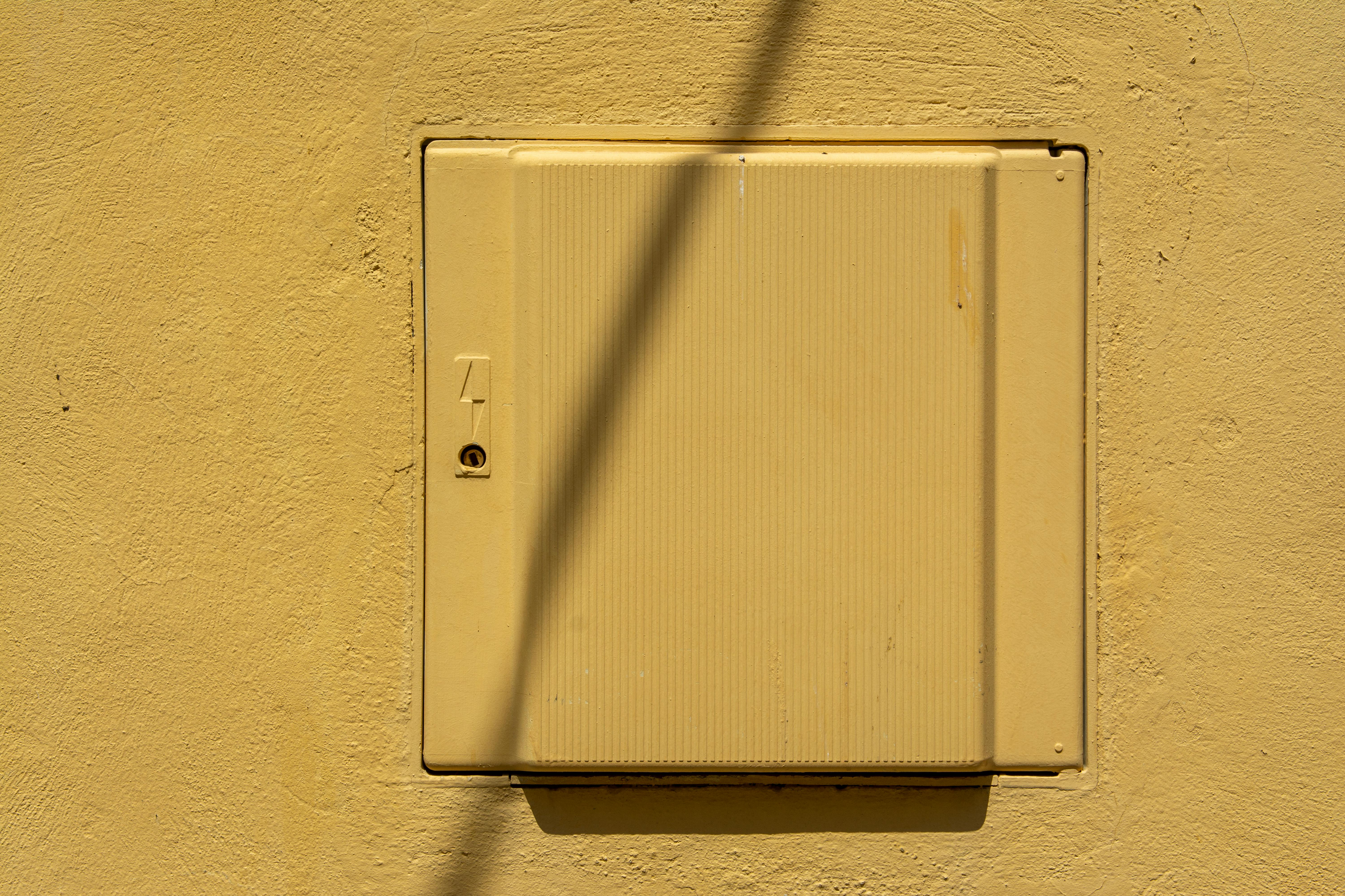 Electricity Shield on Yellow Wall · Free Stock Photo