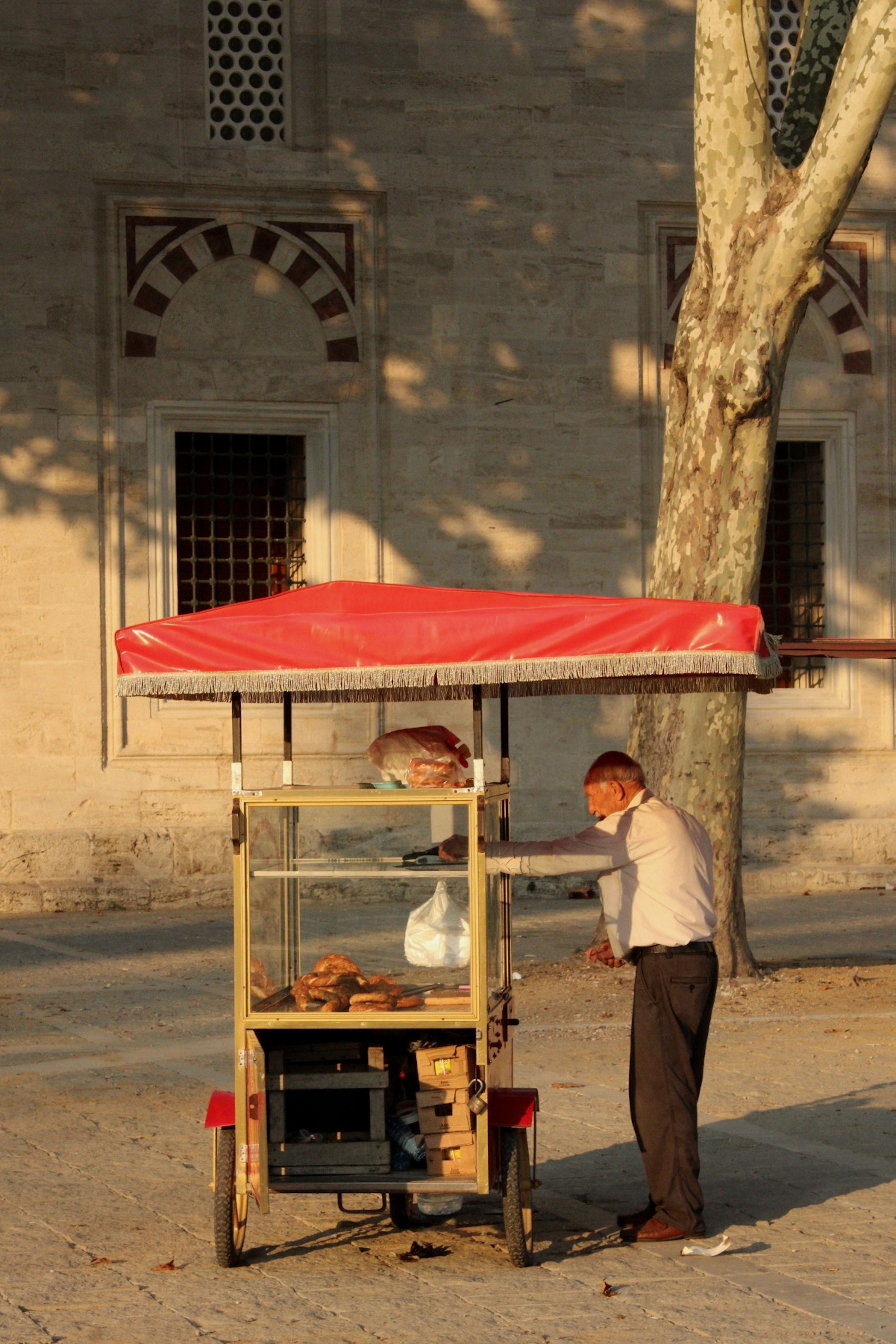 A man selling food from a cart in front of a building · Free Stock Photo