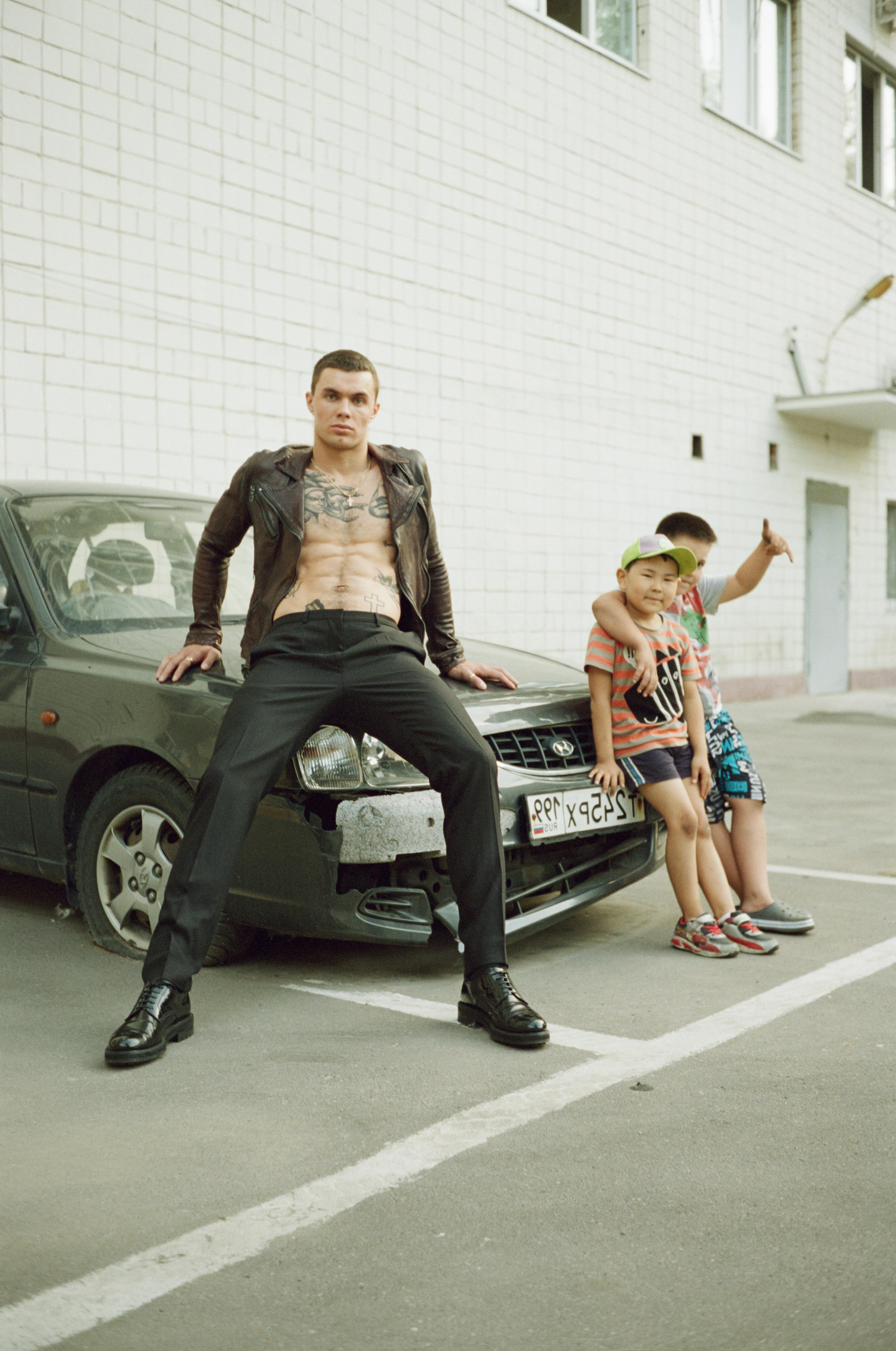 Man and Two Children Leaning Against an Old Broken Car · Free Stock Photo