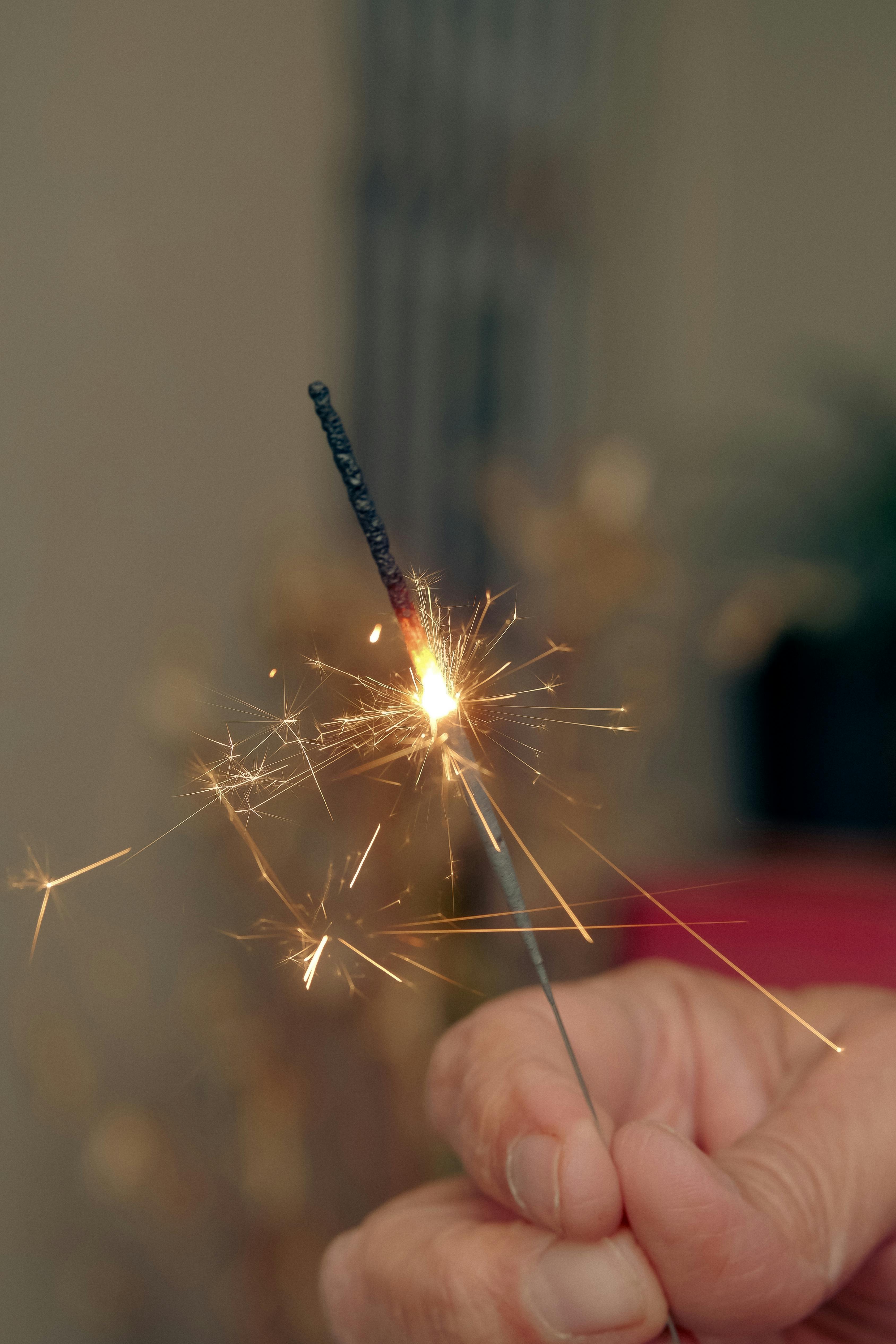 Close-up of Hand Holding a Sparkler Indoors · Free Stock Photo