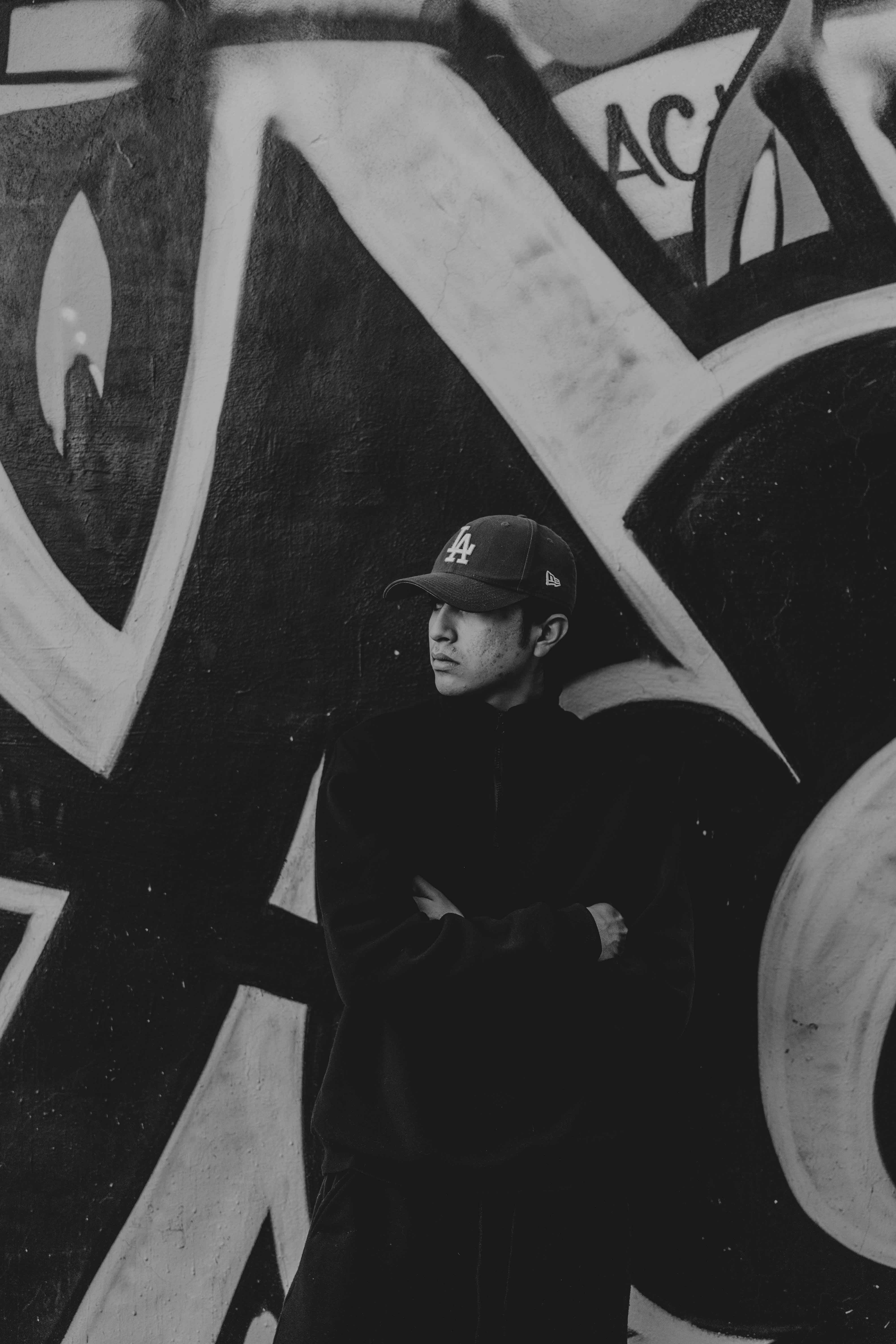 Man in Cap Standing by Wall with Graffiti in Black and White · Free ...