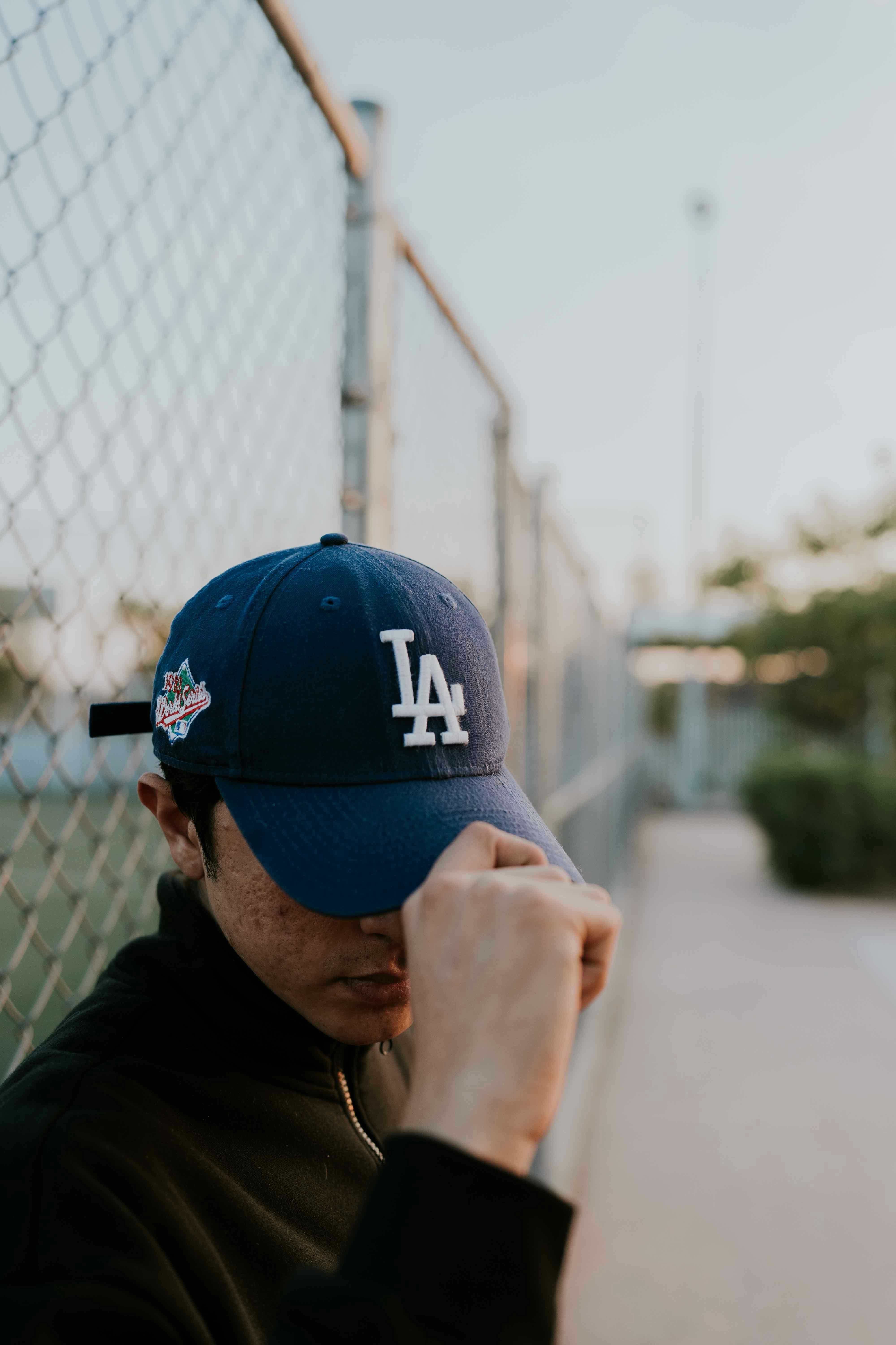 Man Holding Visor of Blue Baseball Cap · Free Stock Photo