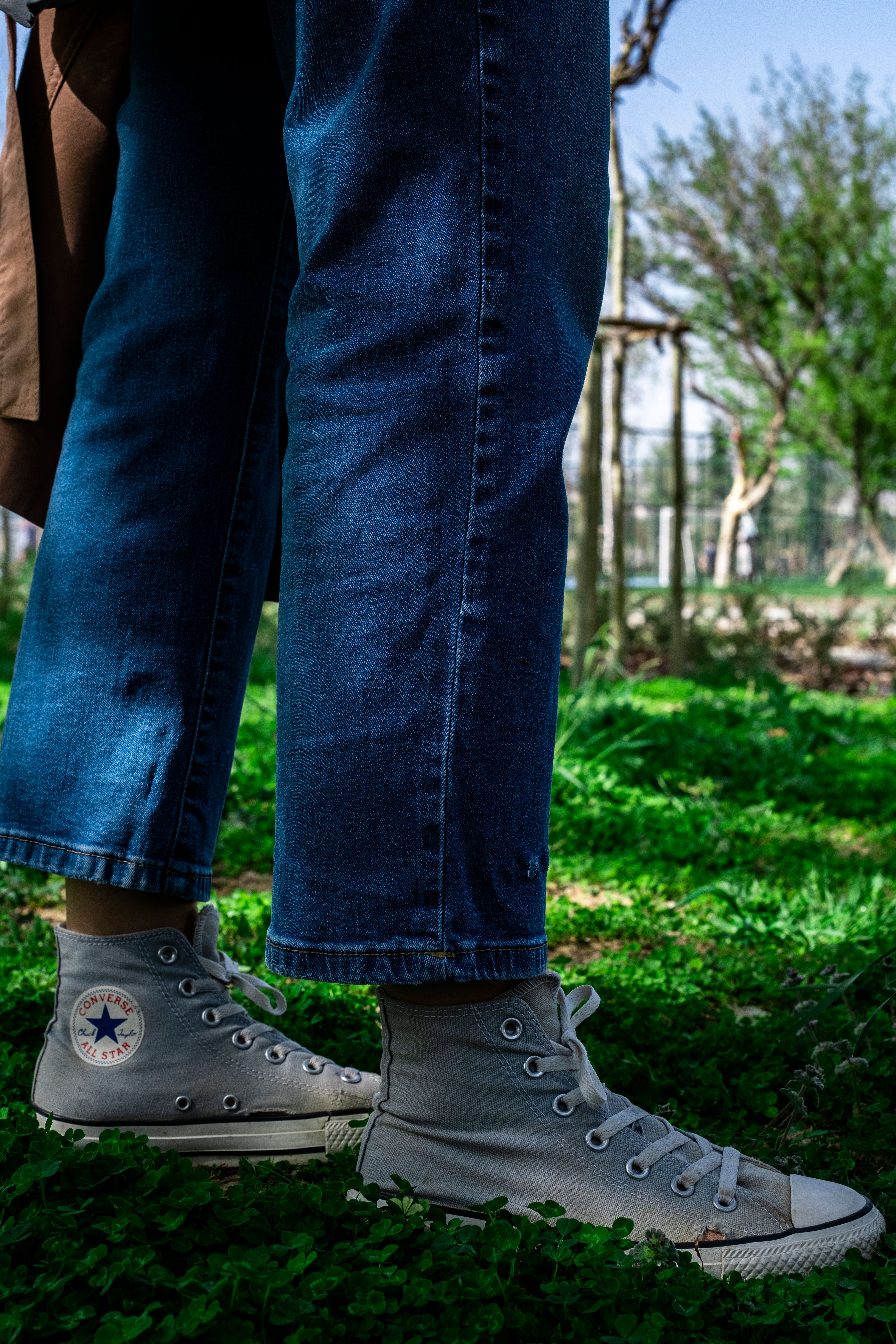 A Person in Denim Jeans Wearing Gray Converse Shoes while Standing on ...