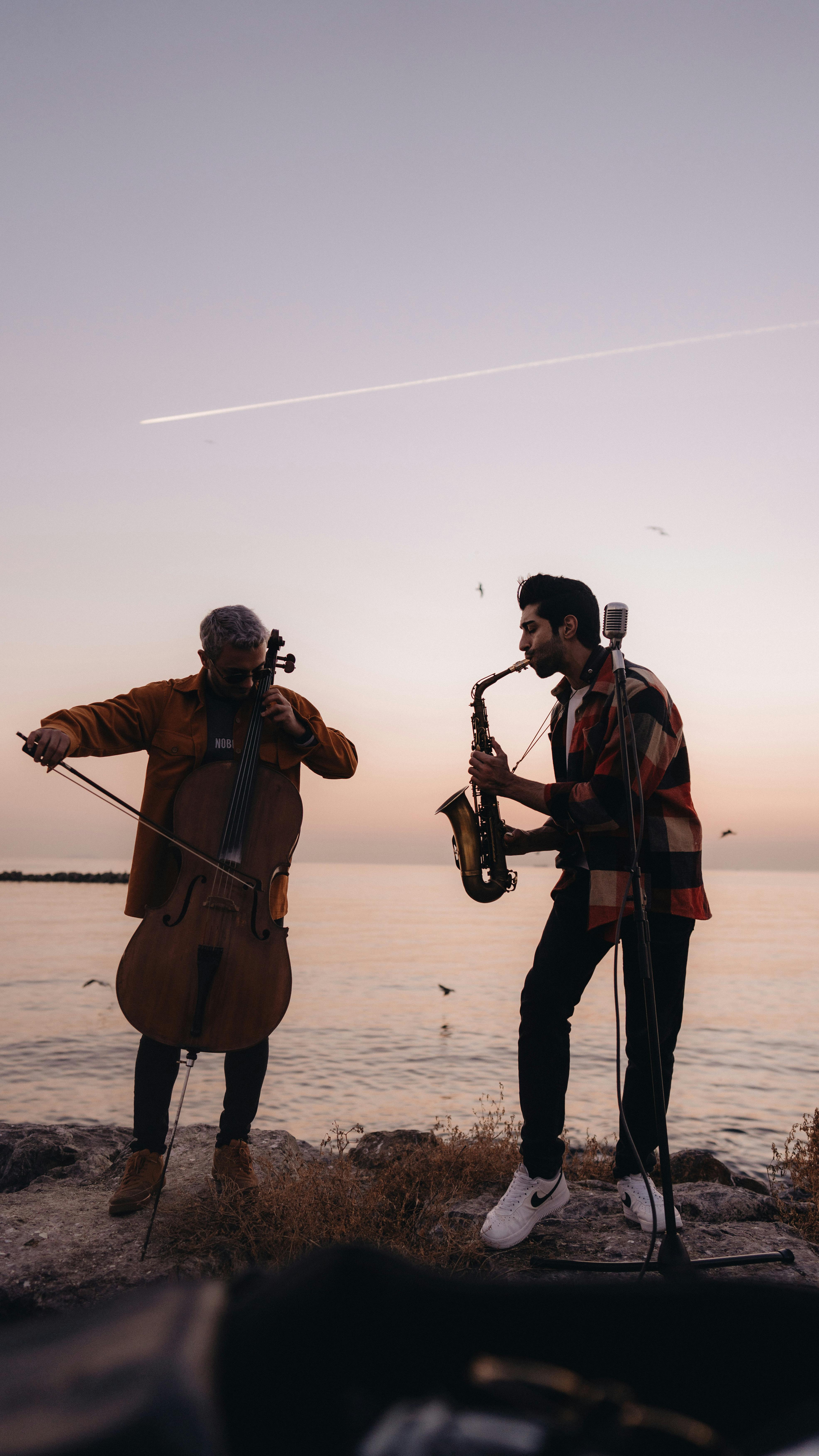 Men Playing Musical Instruments beside Body of Water · Free Stock Photo
