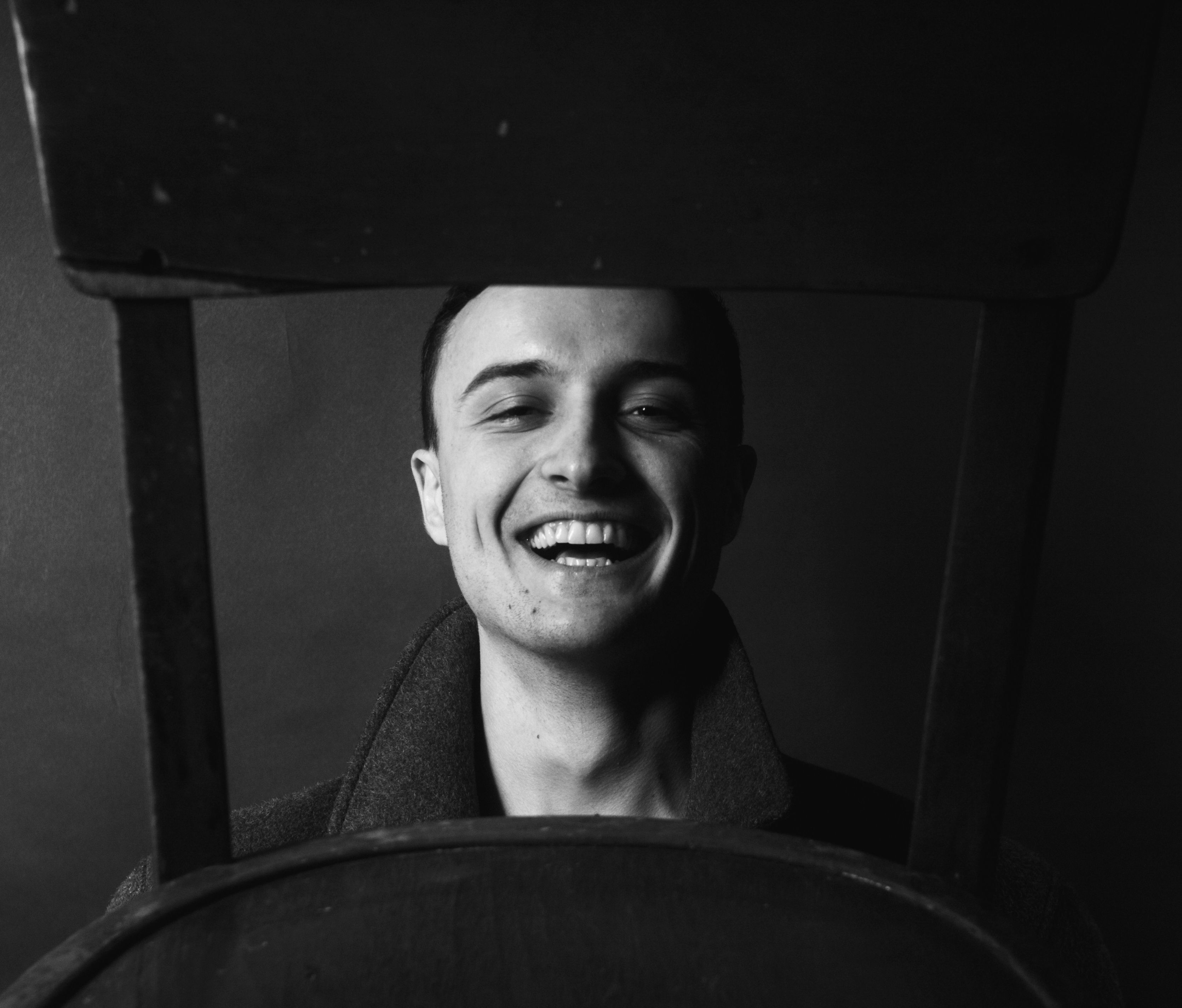 Laughing Man Behind a Chair in Black and White · Free Stock Photo