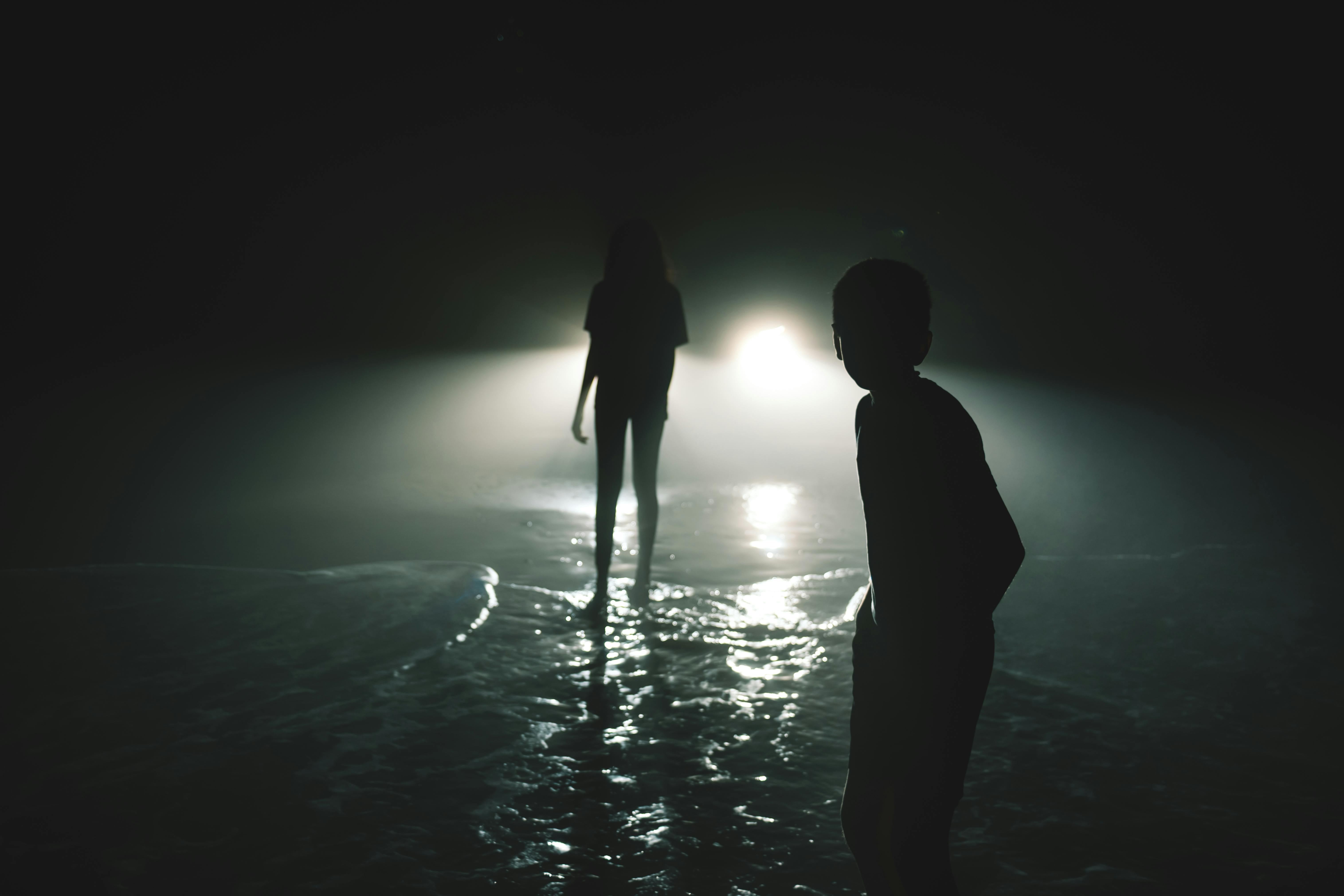 Silhouettes of Two People Standing on the Background of Car Lights at ...