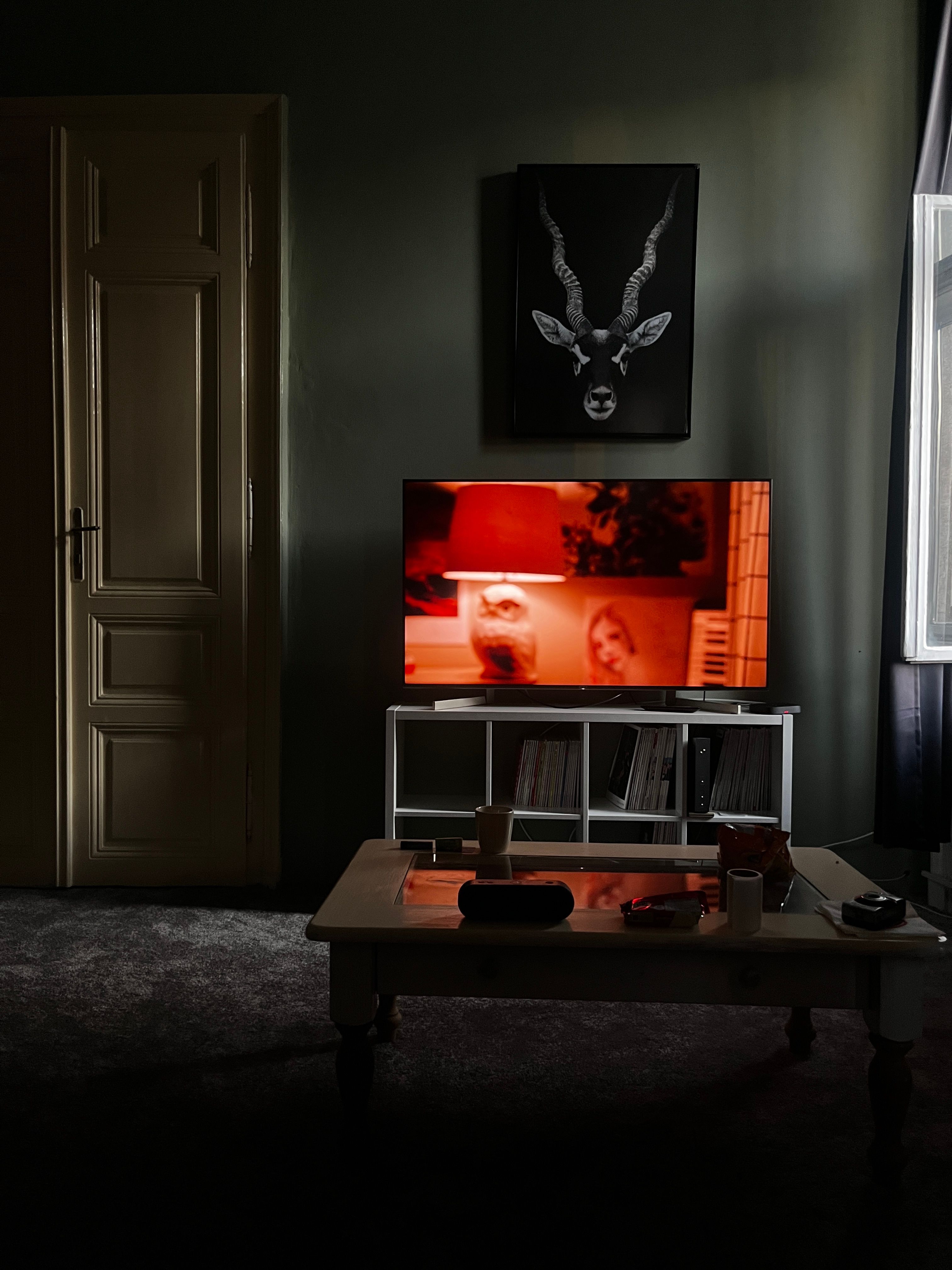 A tv is on in a dark room with a painting on the wall · Free Stock Photo