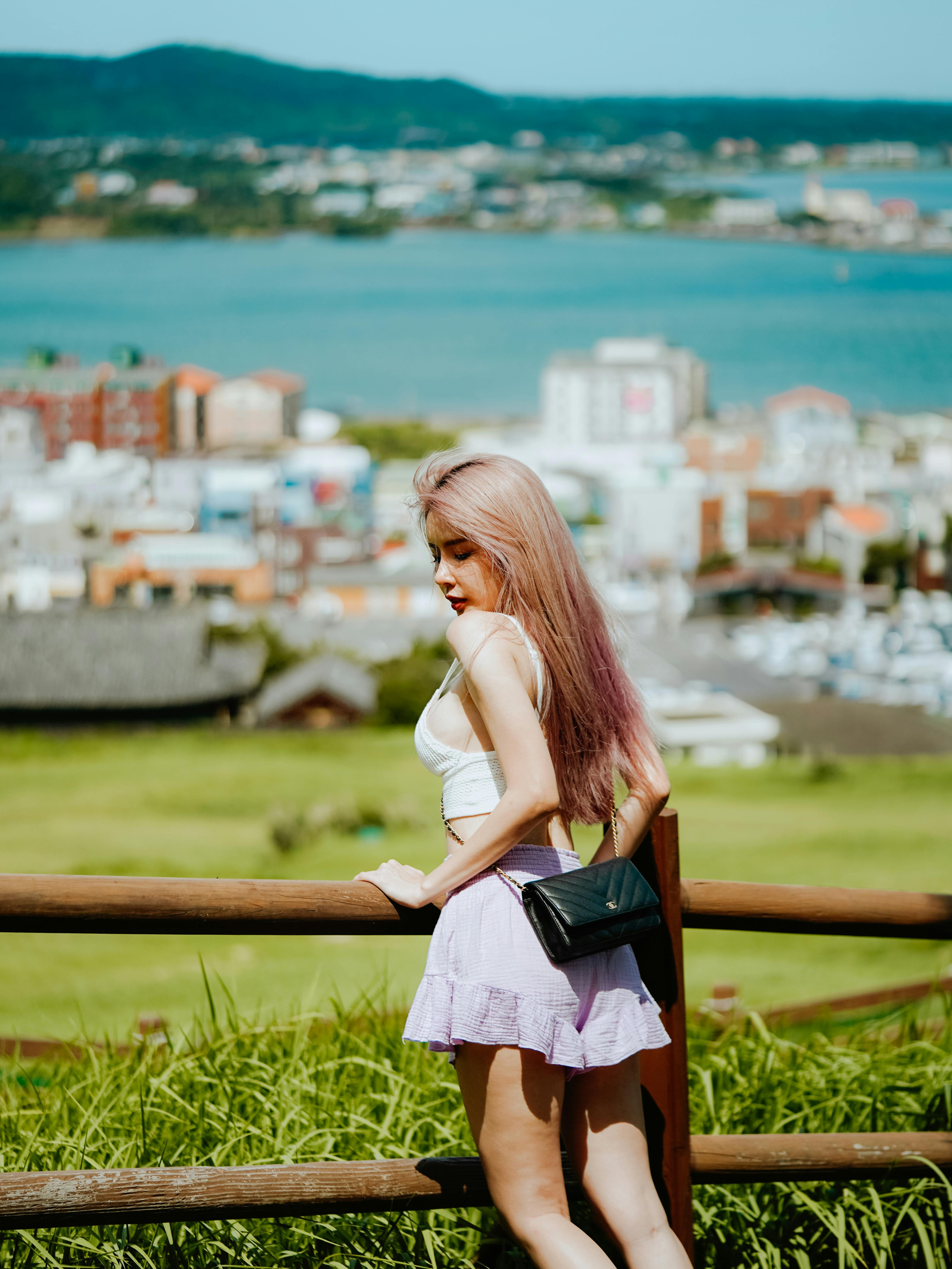 Woman in Sundress Sitting on Wooden Boardwalk Railing · Free Stock Photo